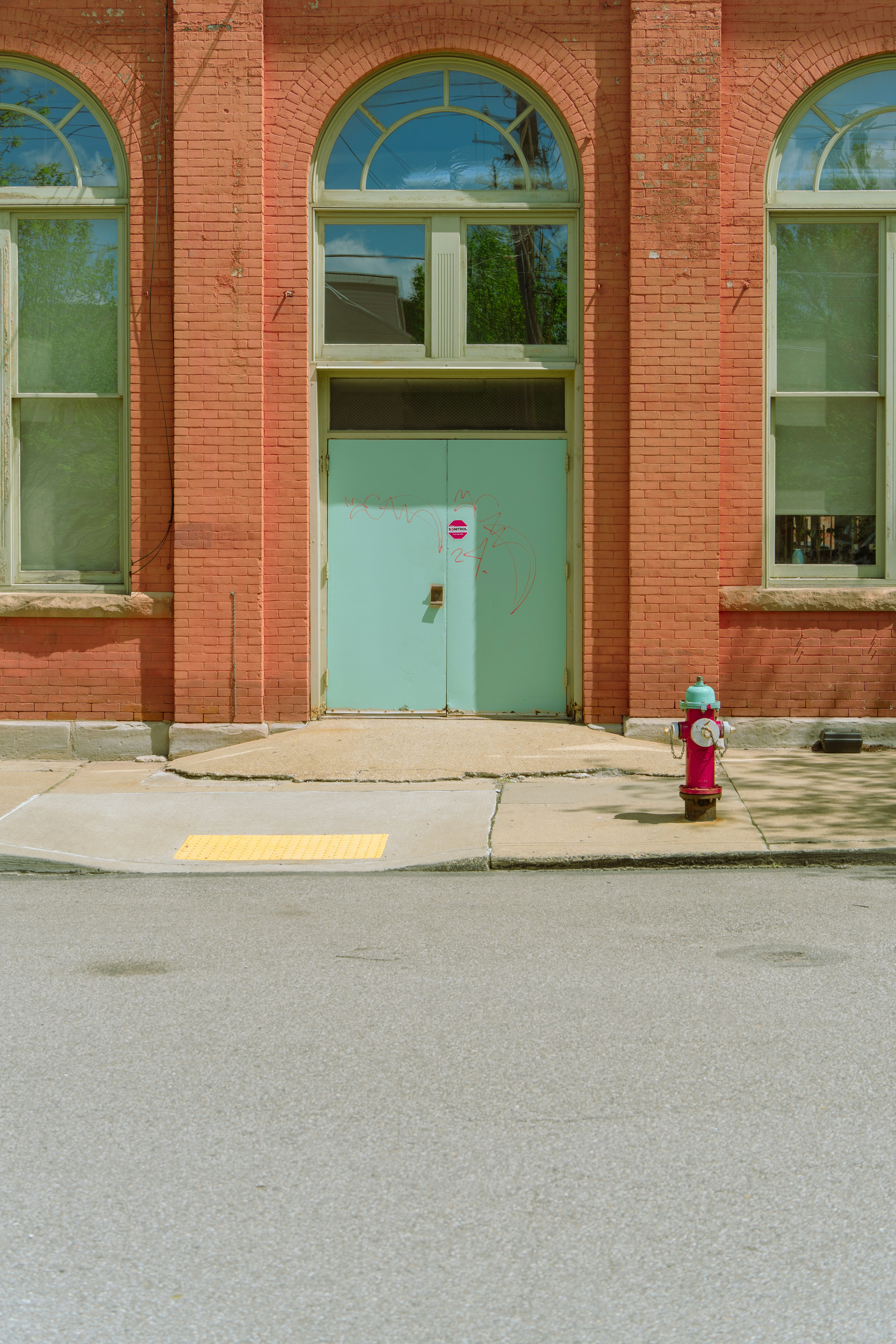 Mint Door Threshold Under Arched Windows on a Red-Brick Facade