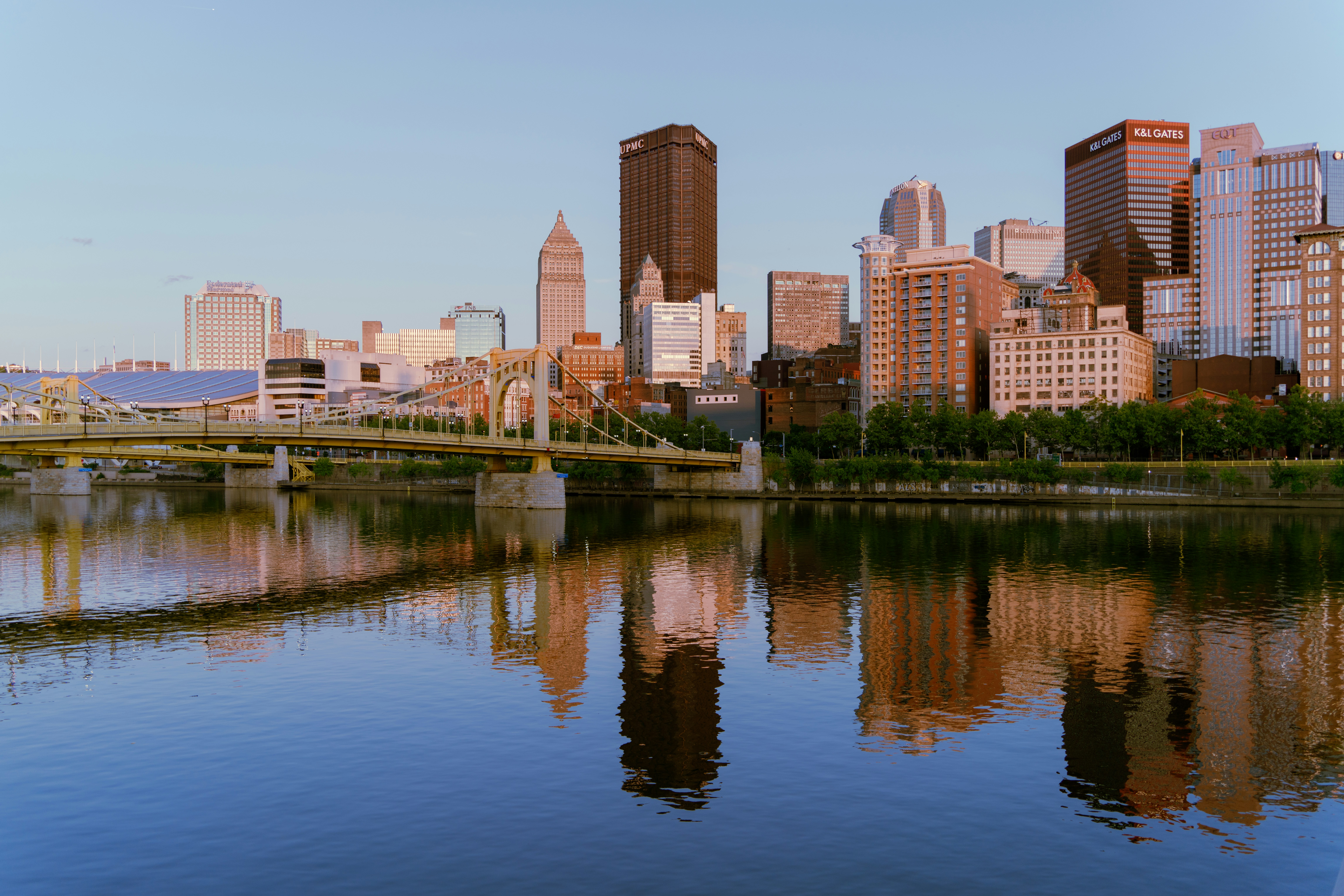City skyline mirrored in a calm river at twilight.