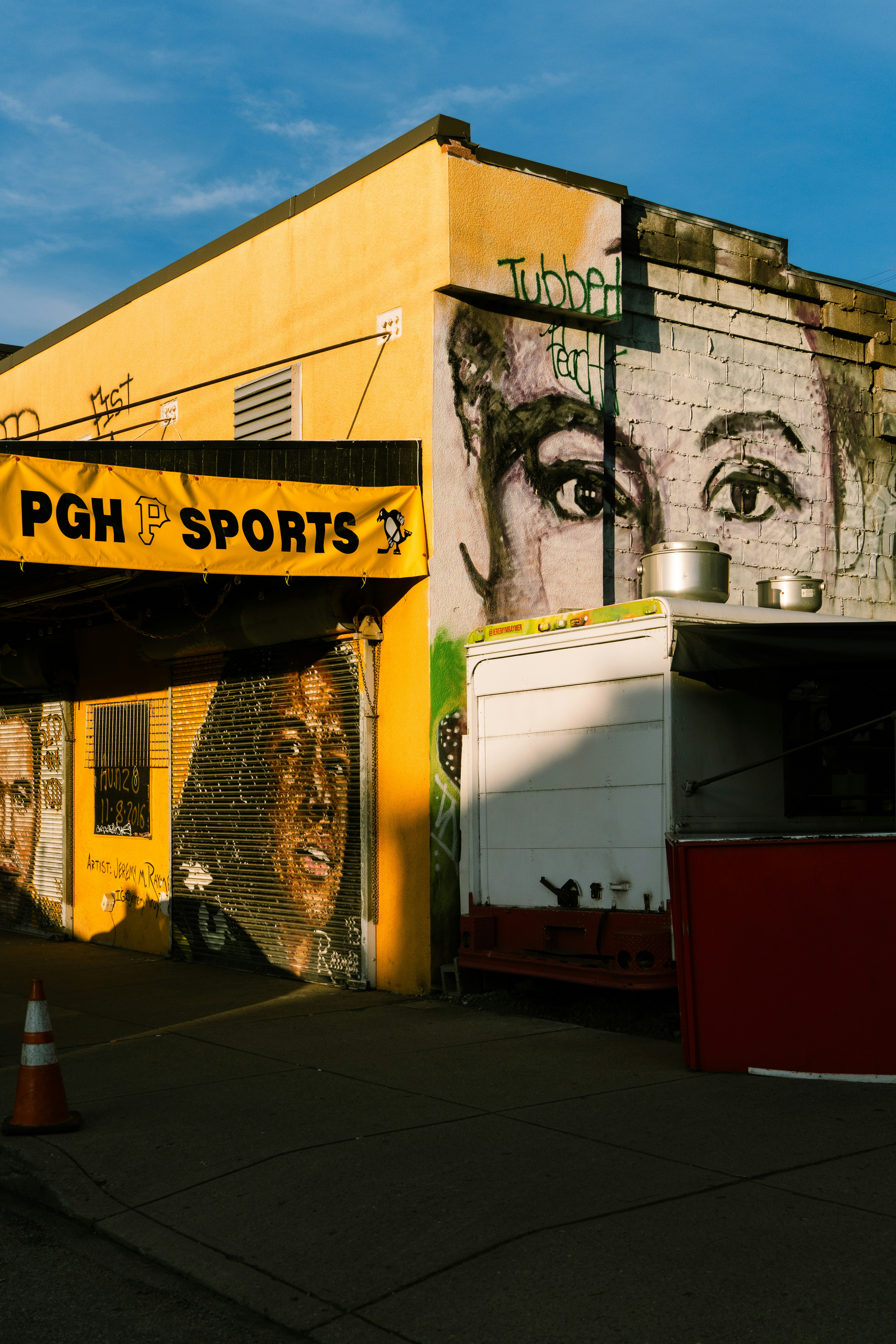 Graffiti Gallery: A Bright Yellow Facade and a Large Portrait at Dusk