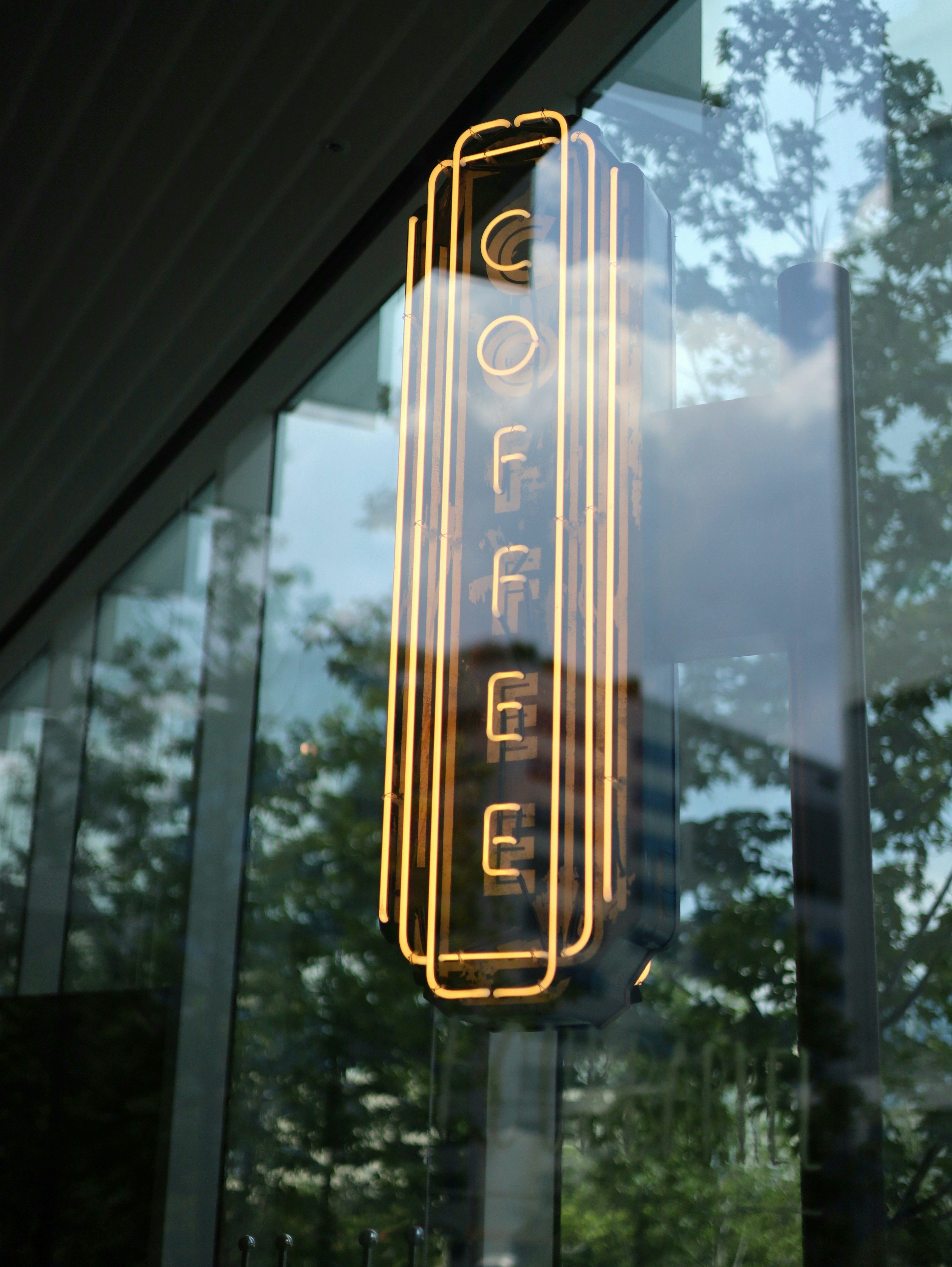Vertical Neon Coffee Sign Framed by Glass and Reflections