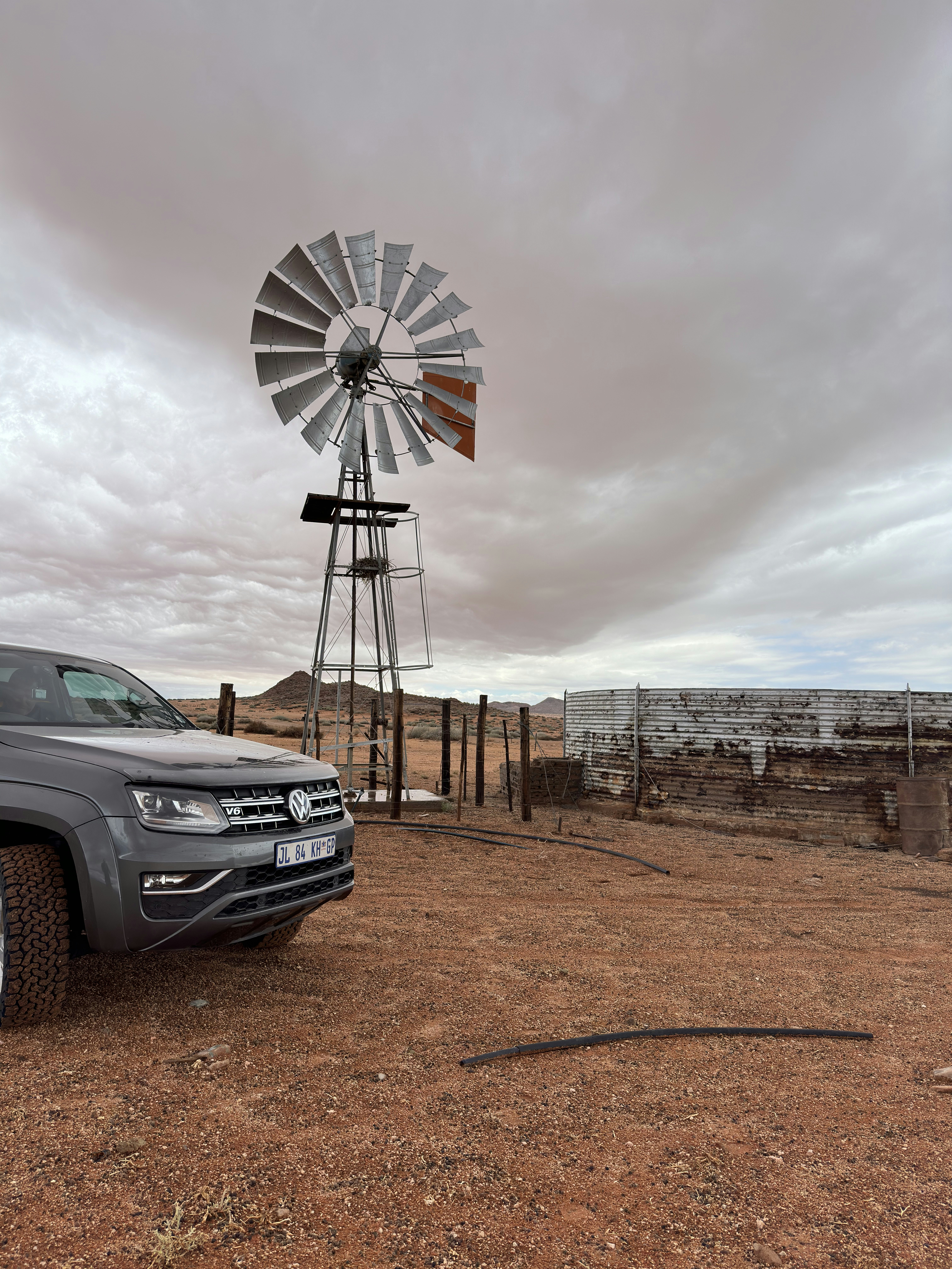 Desert Windmill and a Stalwart Pickup Beneath a Brooding Sky