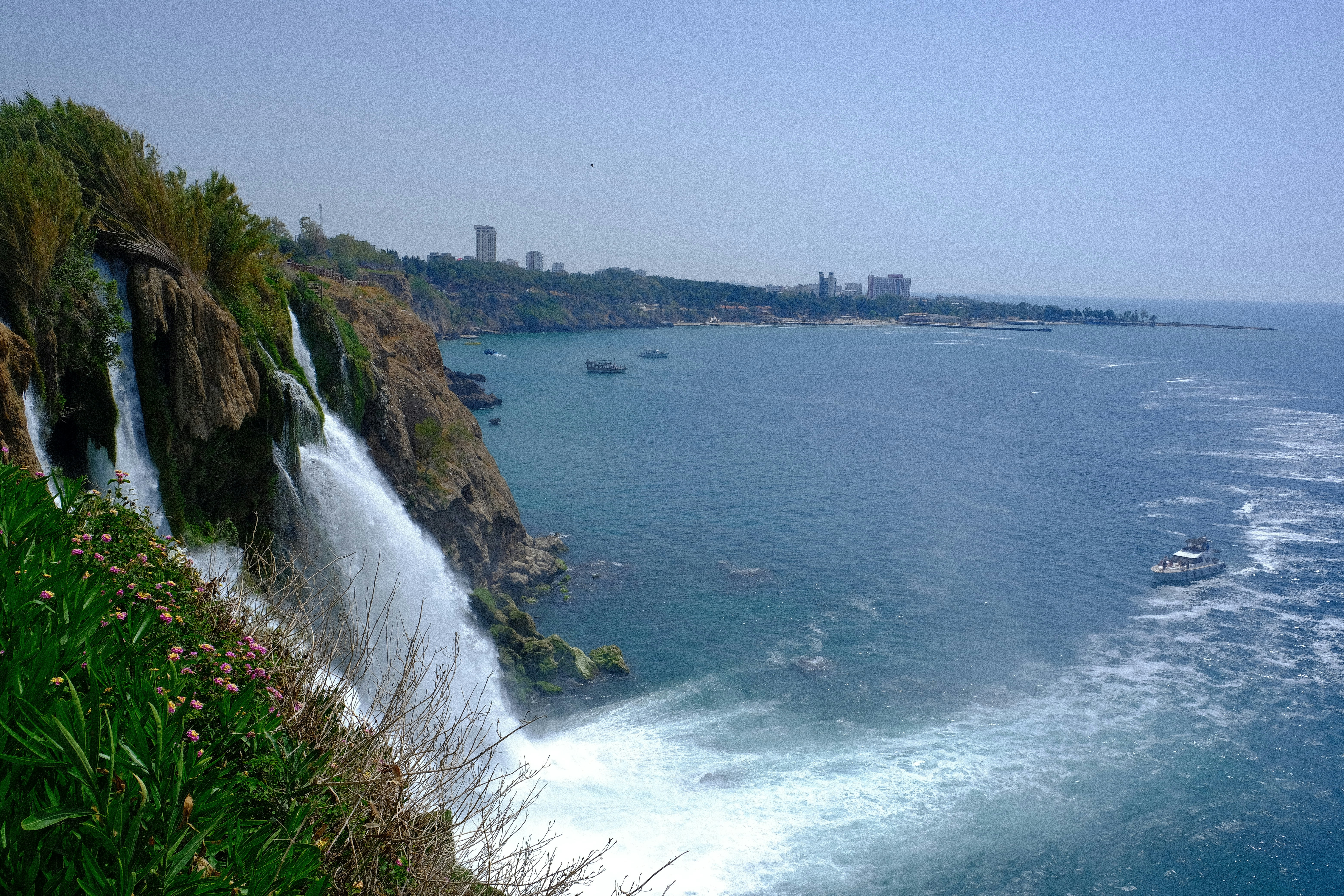 Cliffside Cascades Over Blue Expanse with Distant Skyline