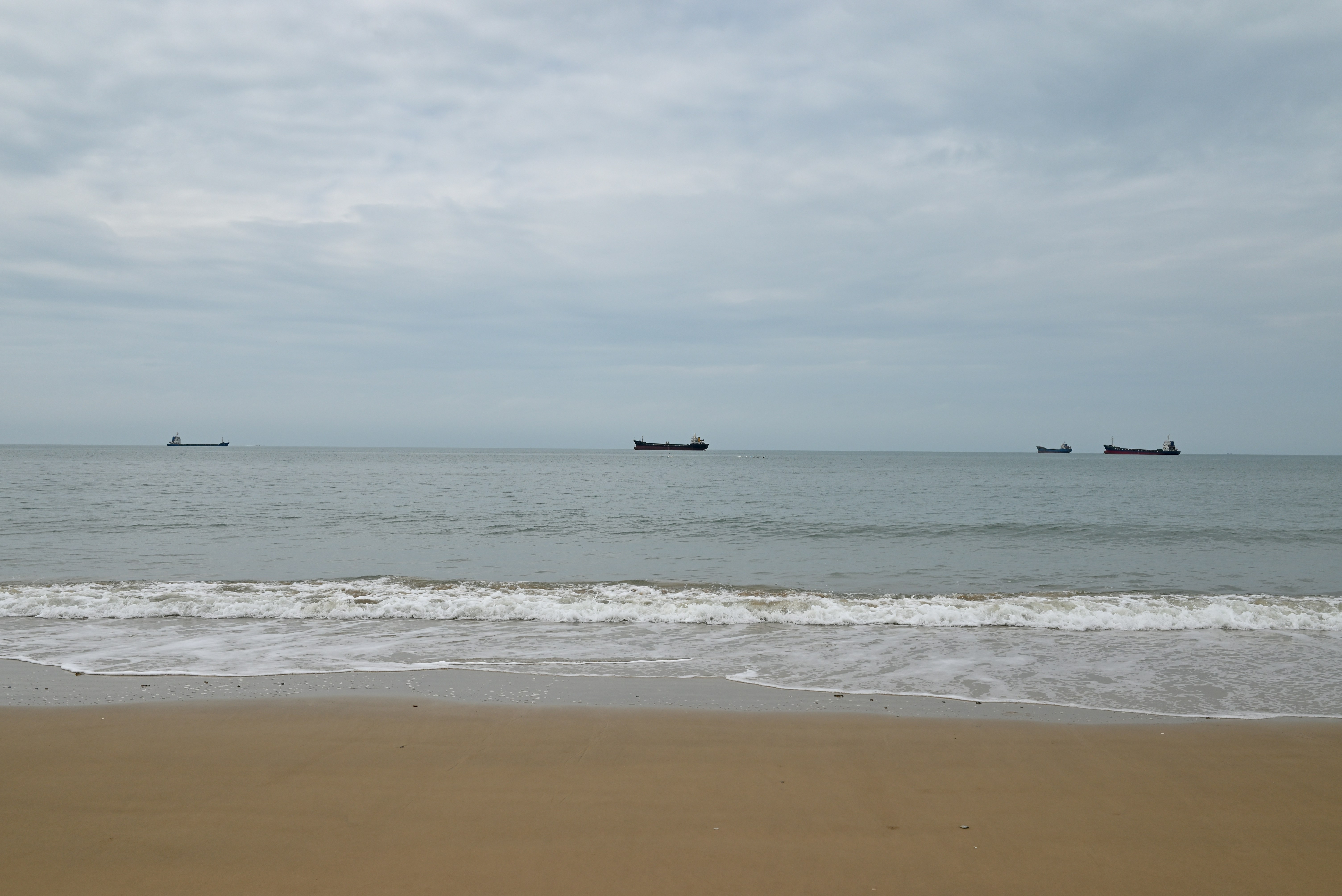 Horizon of Freighters: Four Cargo Ships Crossing a Calm Sea