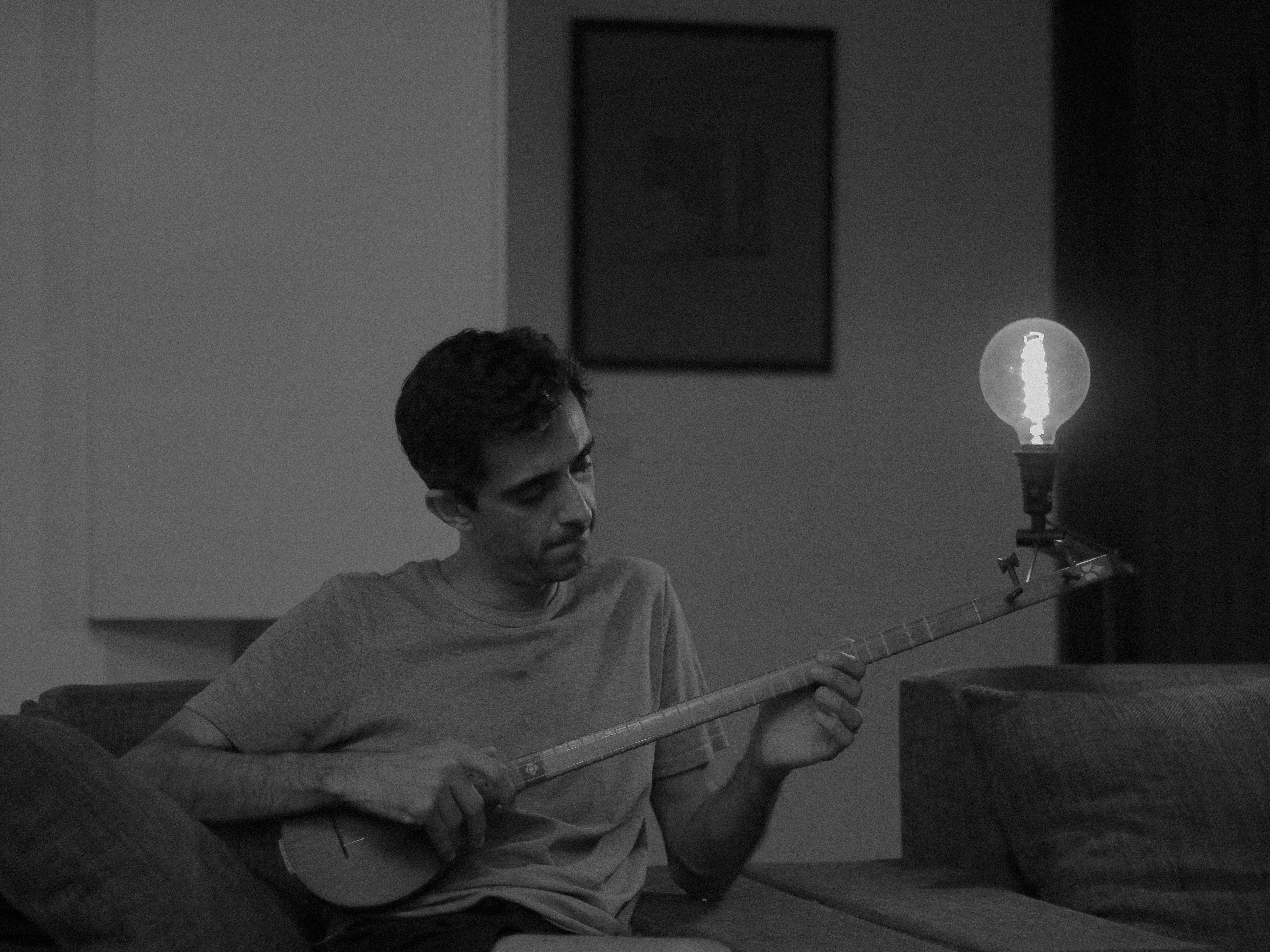 A man sitting on a couch playing a guitar photo – Free Light Image on Unsplash