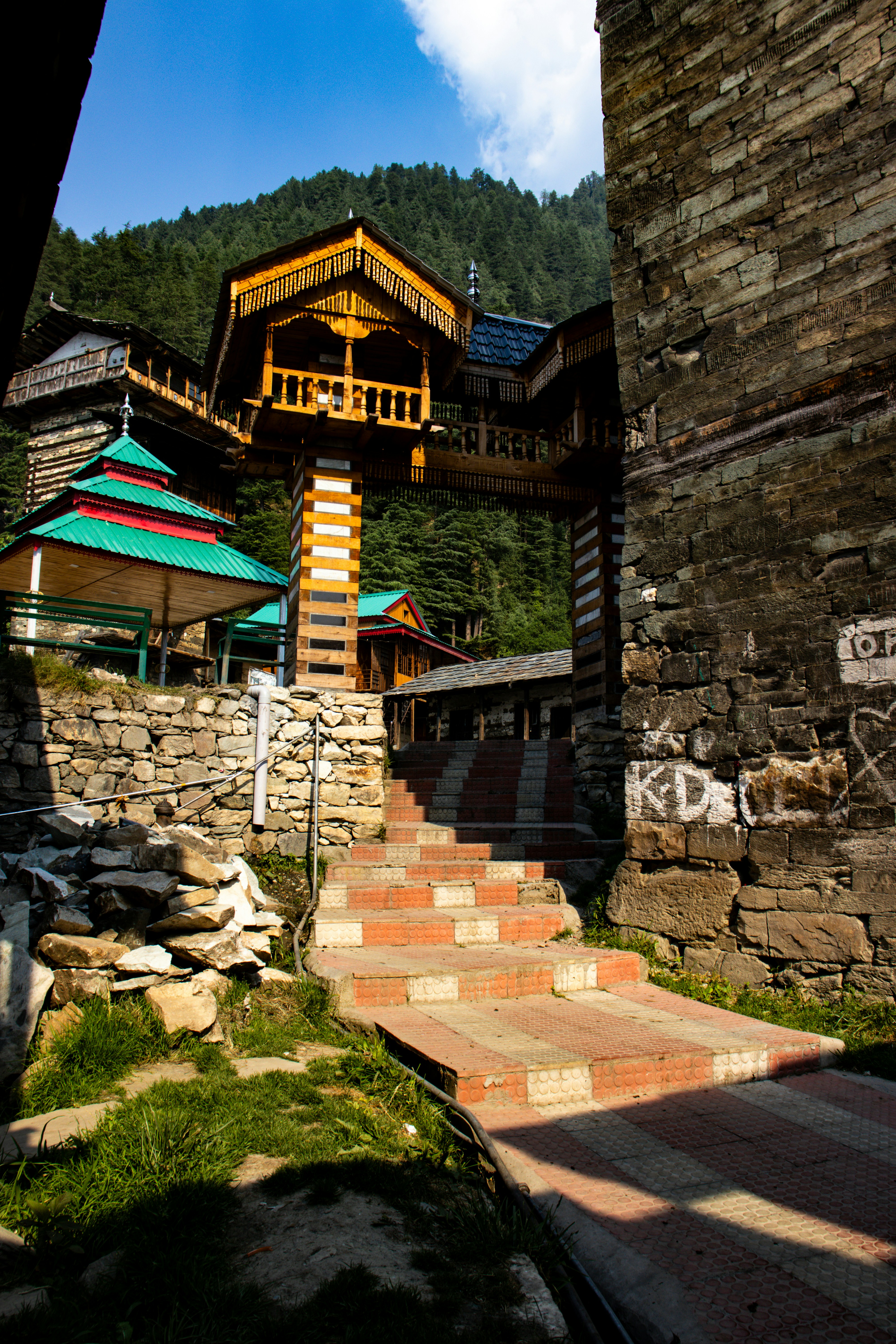 Stone and wood structures with vibrant rooftops against a forested mountain backdrop.