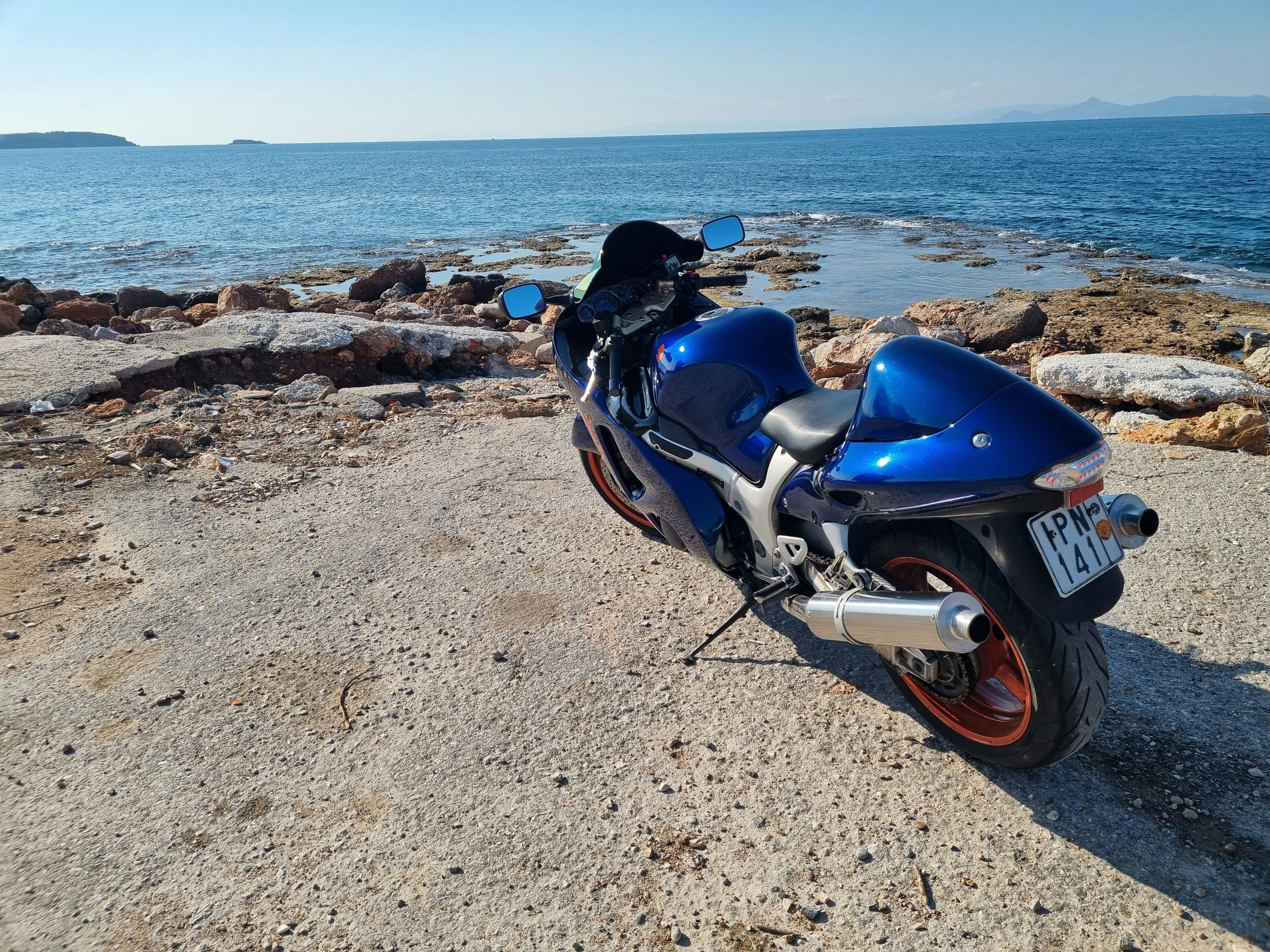 Azure Thunder by the Sea: a blue sportbike resting on sunlit rocky shore