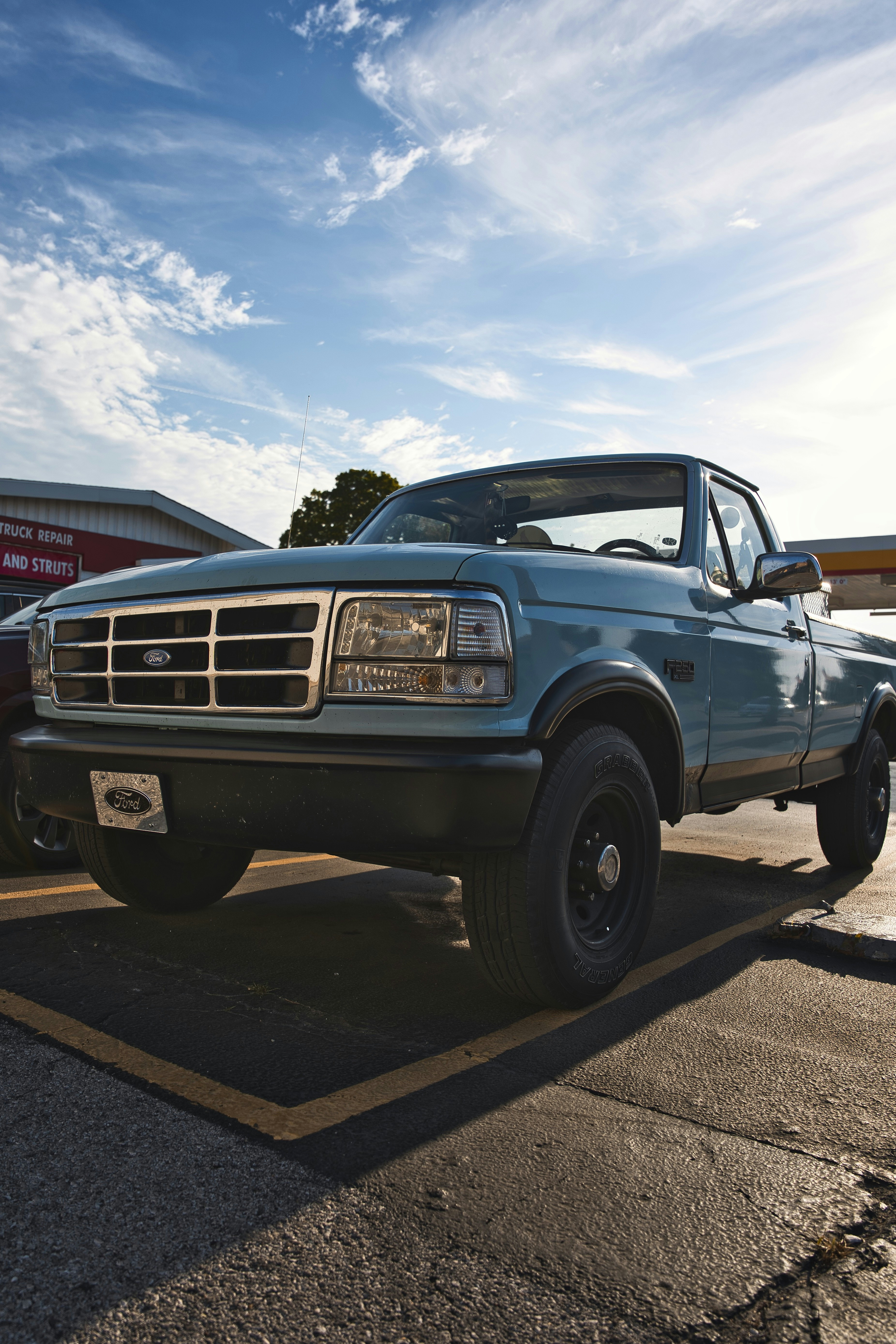 Low-Angle Portrait of a Vintage Blue Ford Pickup in a Sunlit Lot