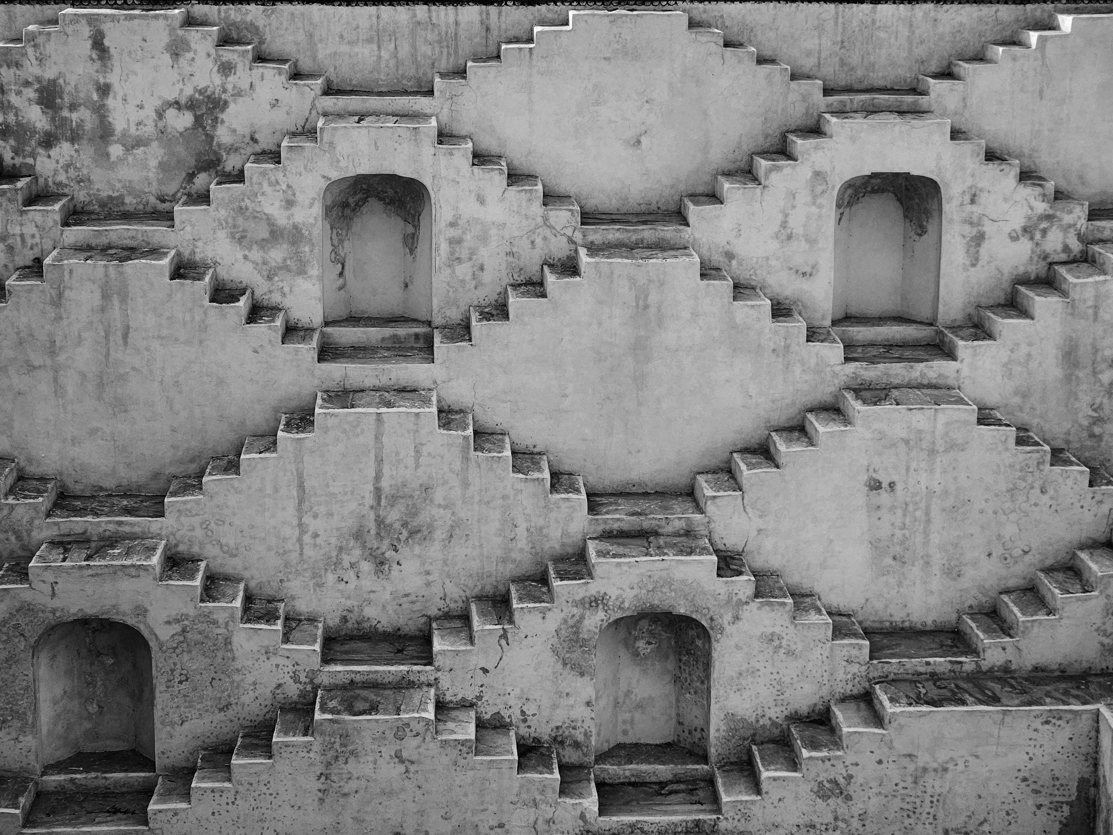 Symmetrical pattern of ancient stepwell stairs with arched doorways.