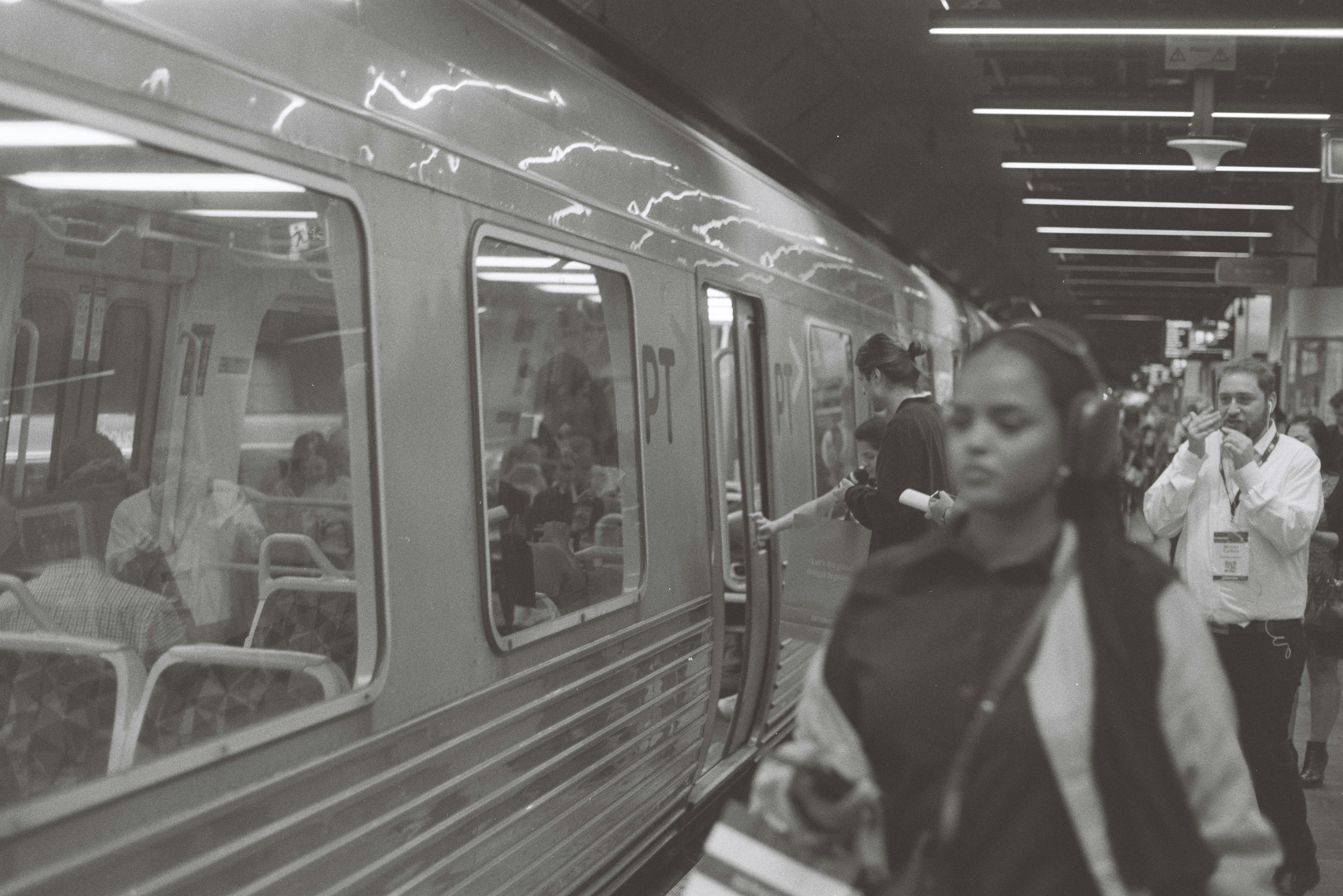 Grayscale Momentum: A commuter strides beside a waiting metro