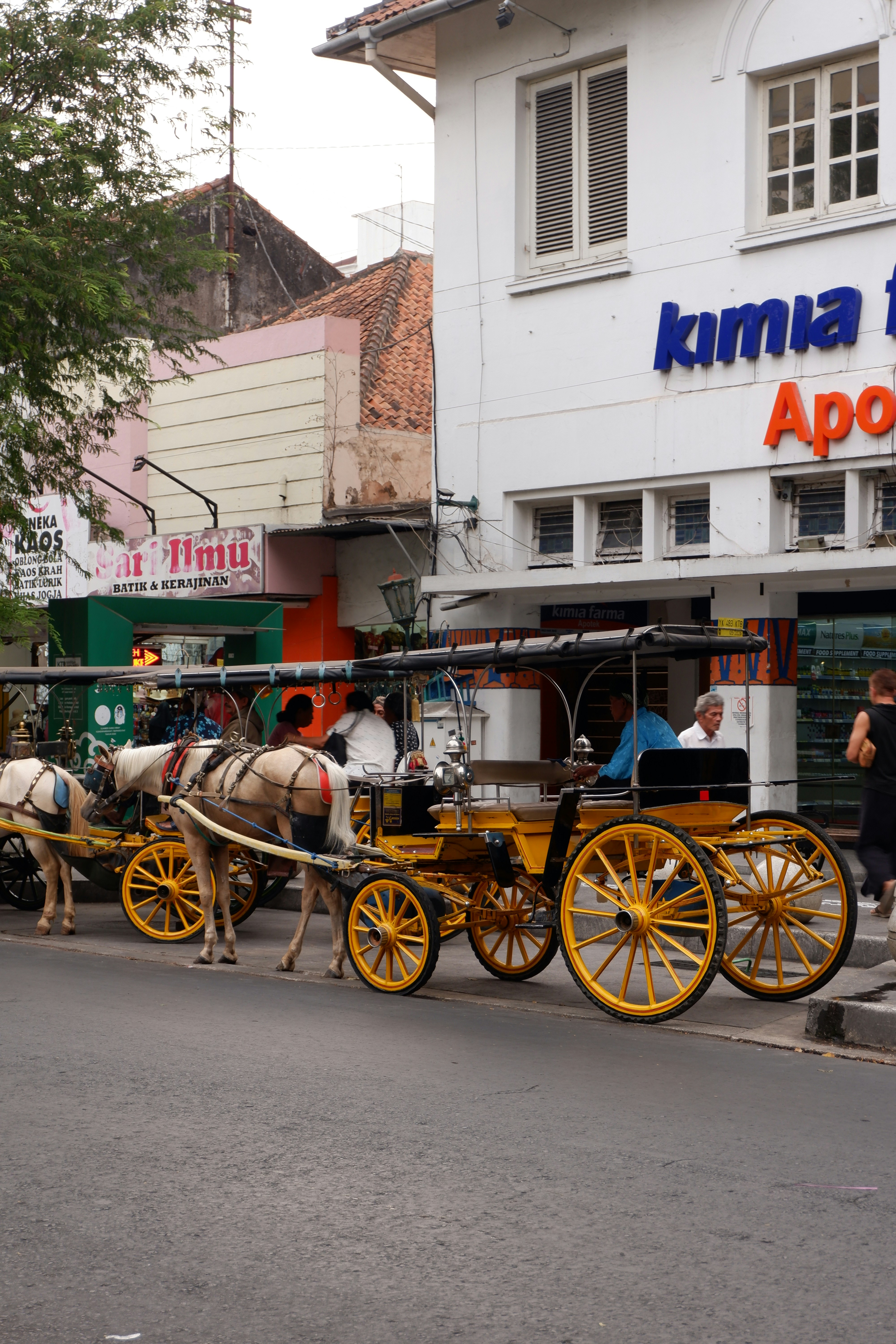 Sunlit Carriage Row: Horses and Bright Yellow Wheels on a Bustling Street
