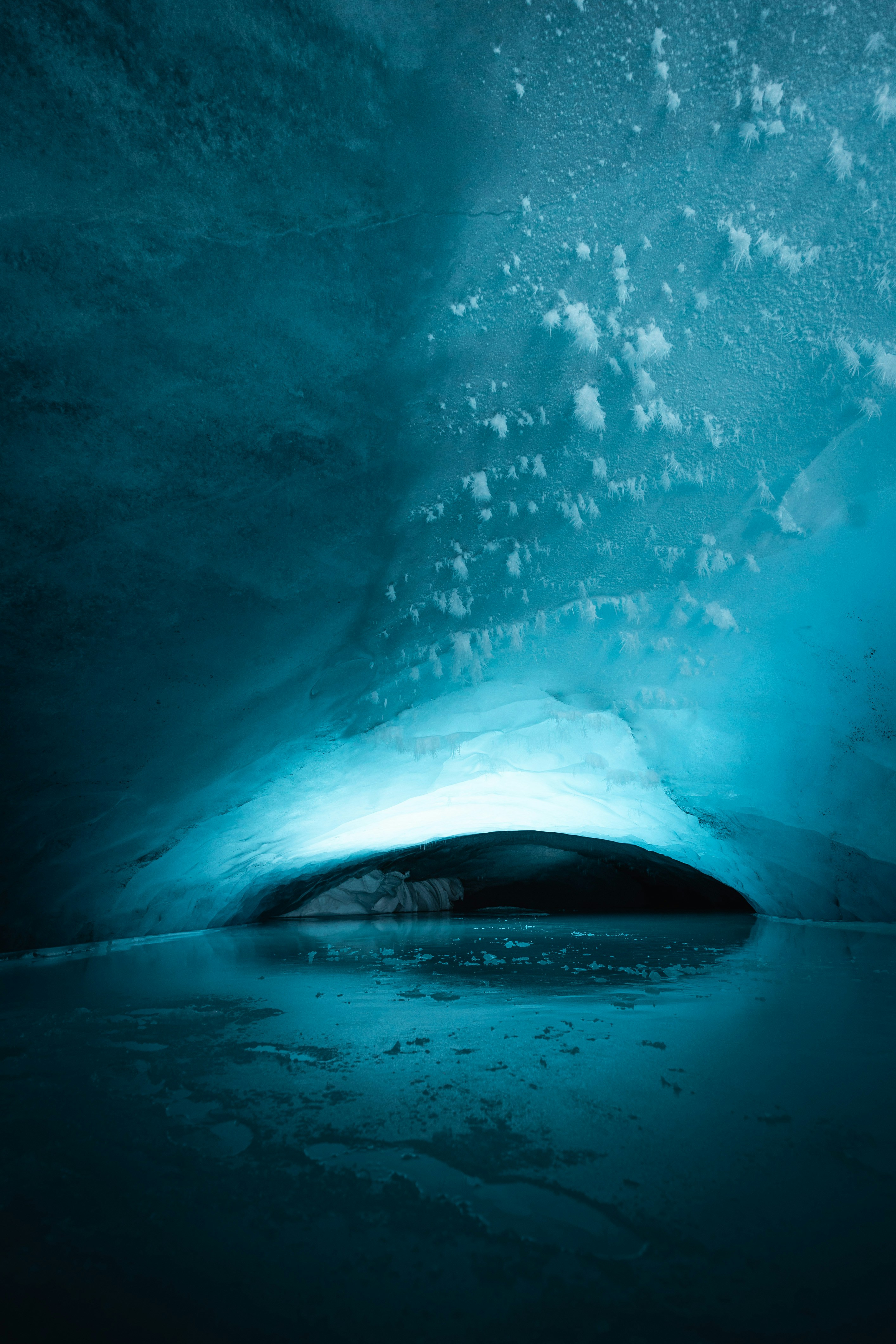 A large ice cave with a blue light coming out of it photo – Free Sea ...