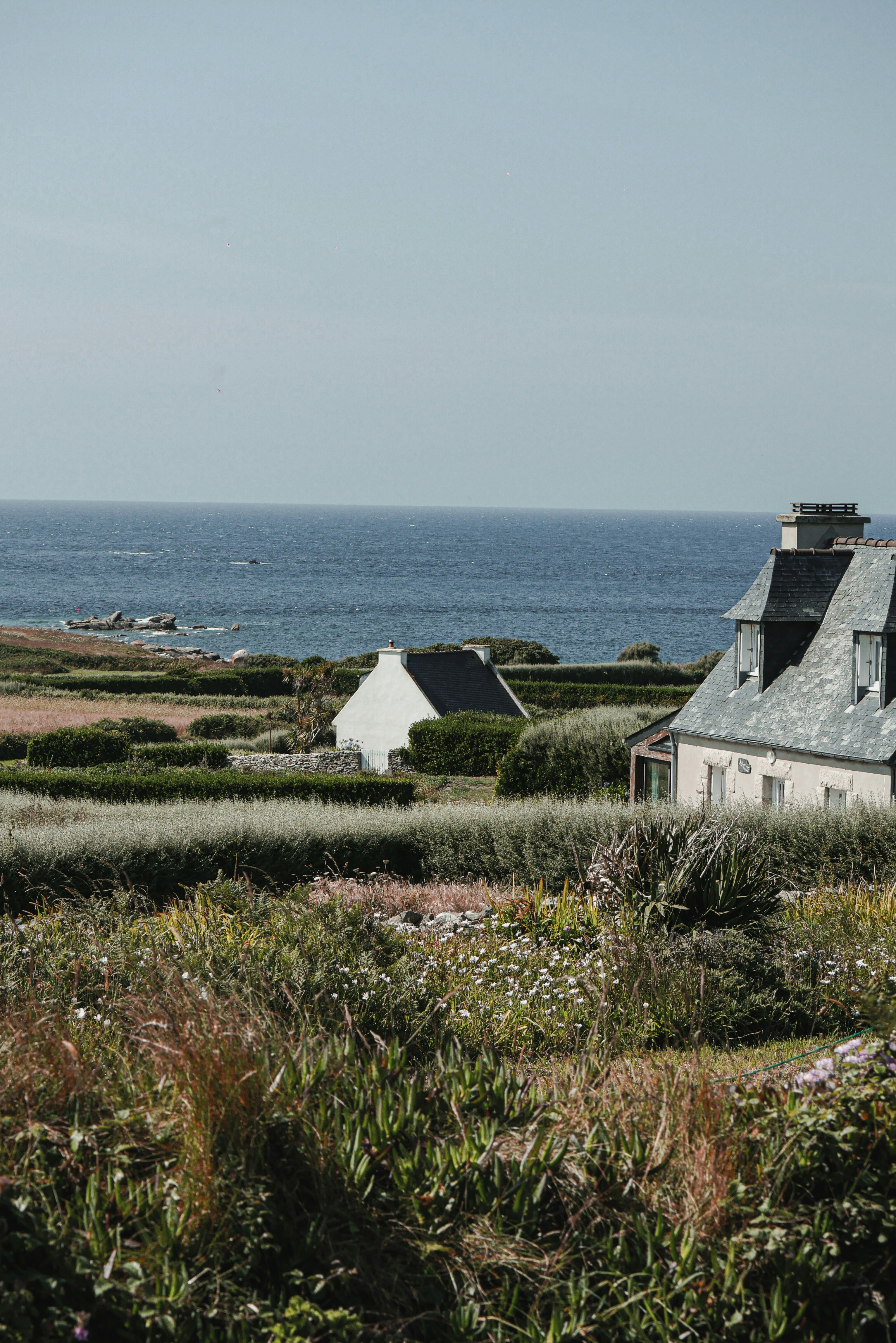 A house sitting on top of a lush green field next to the ocean photo ...