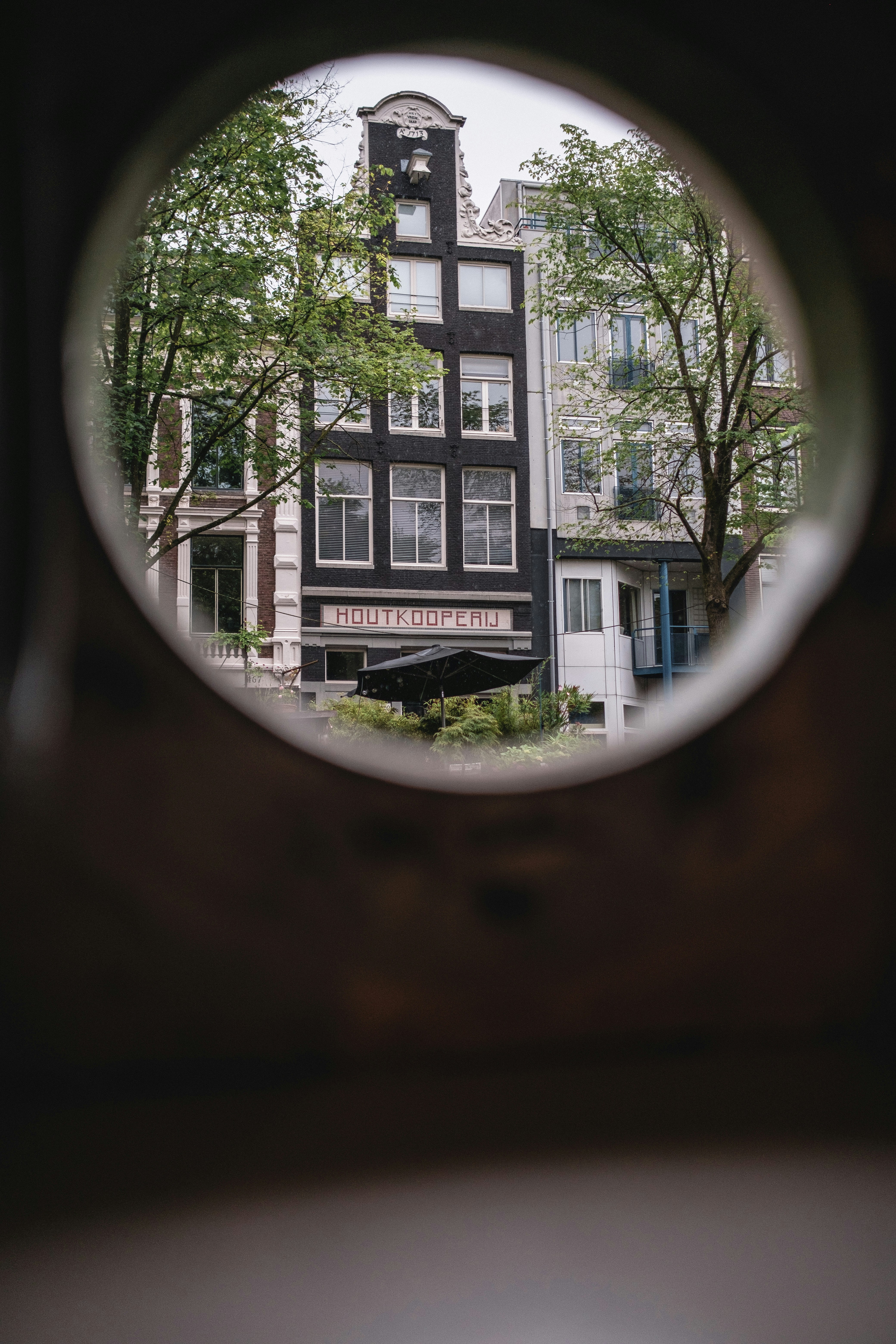 A view from a porthole on a houseboat on the canals of Amsterdam | A view of a building through a round window