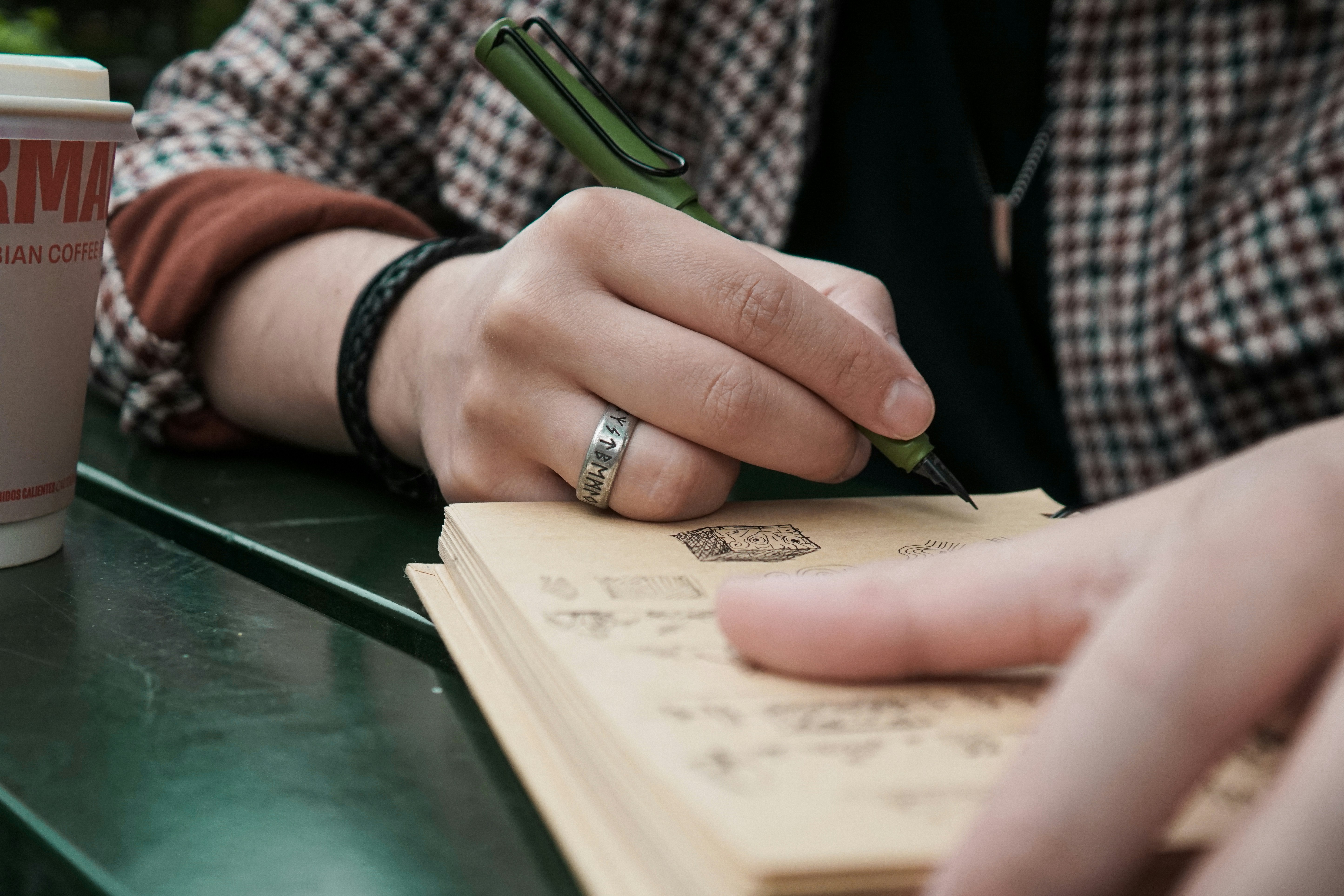 A person sitting at a table writing on a notebook