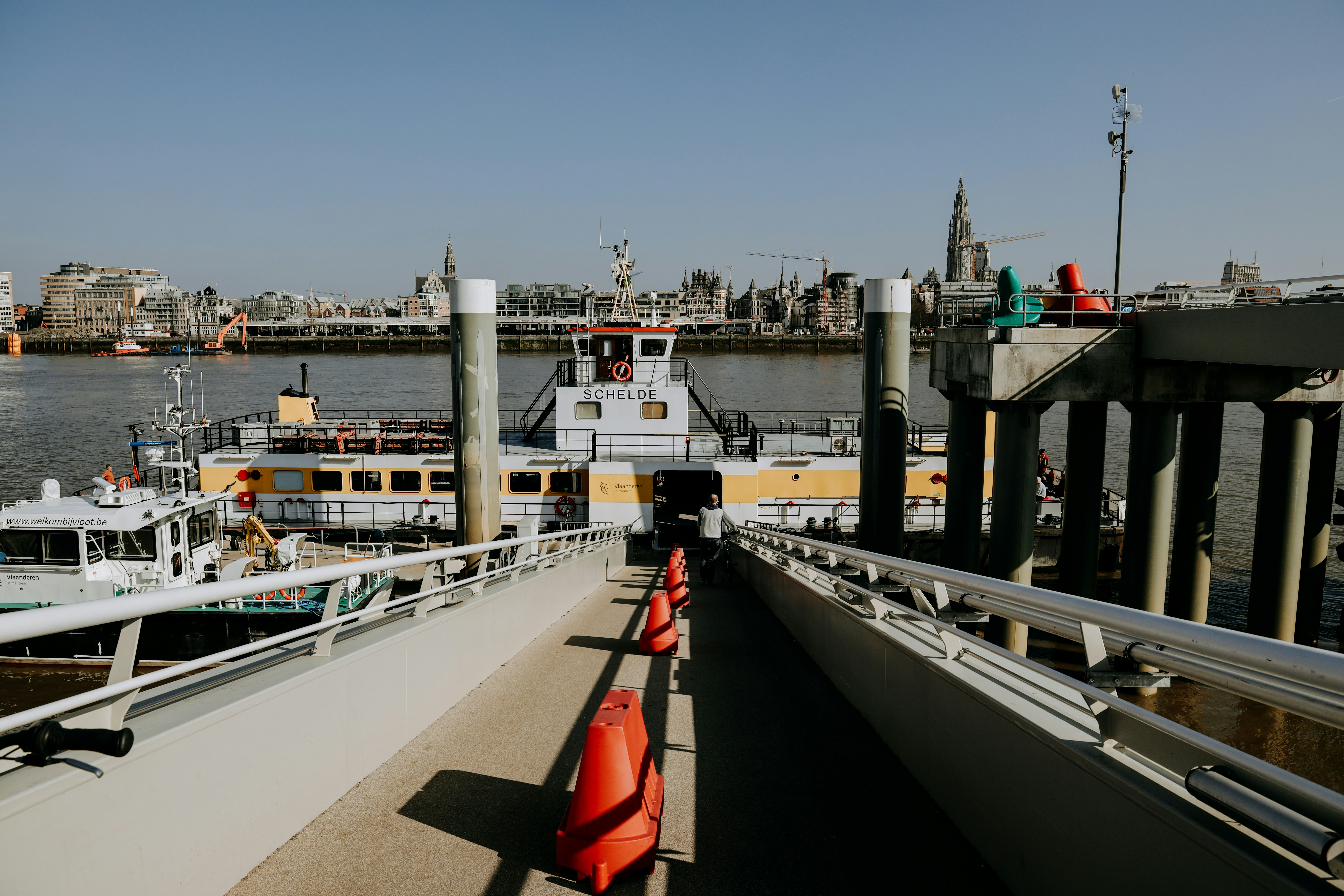 A boat traveling down a river next to a bridge photo – Free Antwerp ...