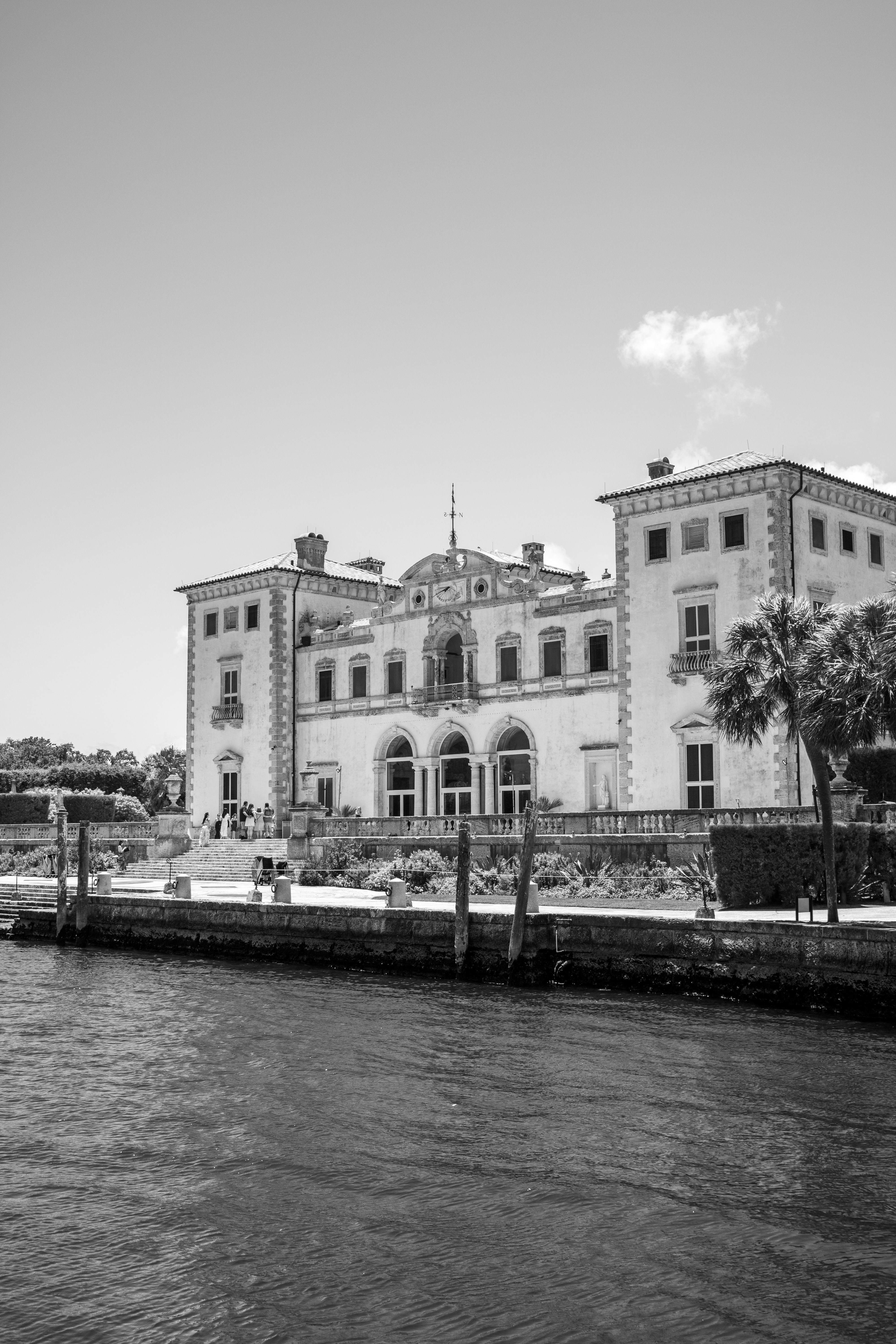 The Vizcaya Museum and Gardens, located in the Coconut Grove neighborhood of Miami, Florida, is an exquisite example of Mediterranean Revival architecture infused with Italian Renaissance influences. Built between 1914 and 1922 as the winter residence of industrialist James Deering, Vizcaya encompasses 34 decorated rooms filled with European antiques and art dating from the 16th to the 19th centuries. The estate originally spanned 180 acres, although today it covers approximately 50 acres, with 10 acres of formal gardens, extensive native woodlands, & a historic village outbuildings compound.