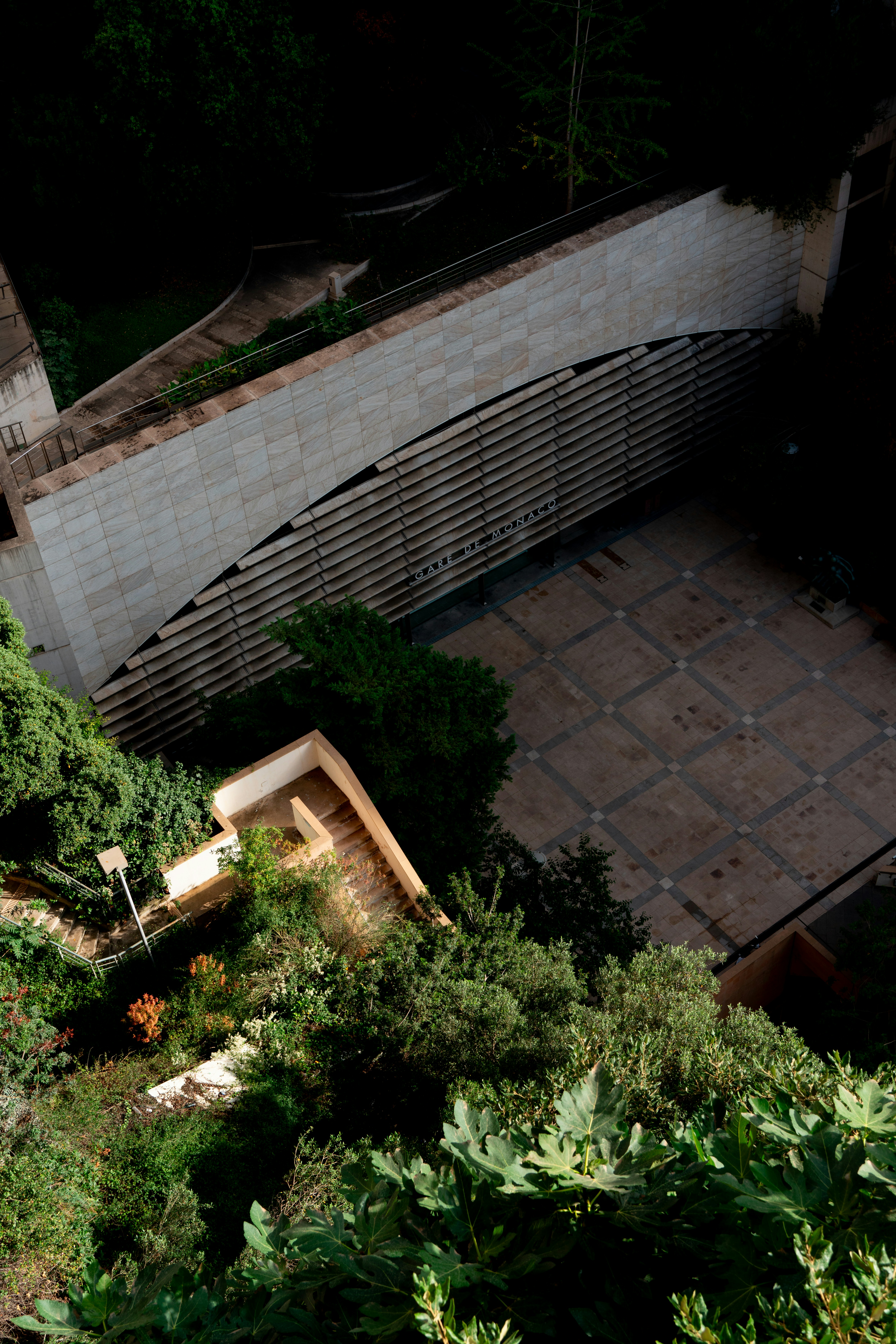 Curved Facade Overlook: Green Canopy Framing a Tile-Courtyard Atrium