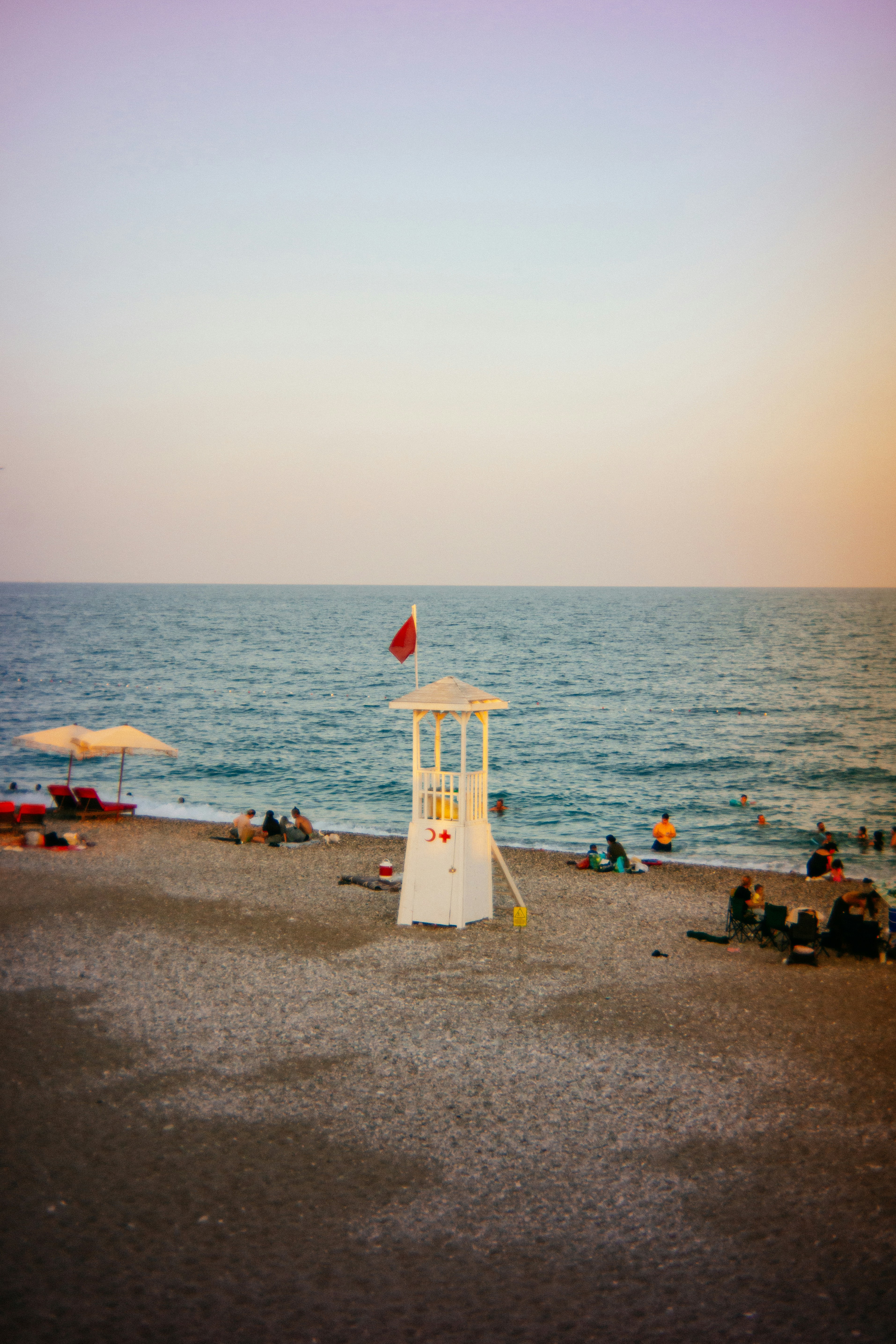 Quiet Vigil at Sunset: White Lifeguard Tower on a Pebble Beach