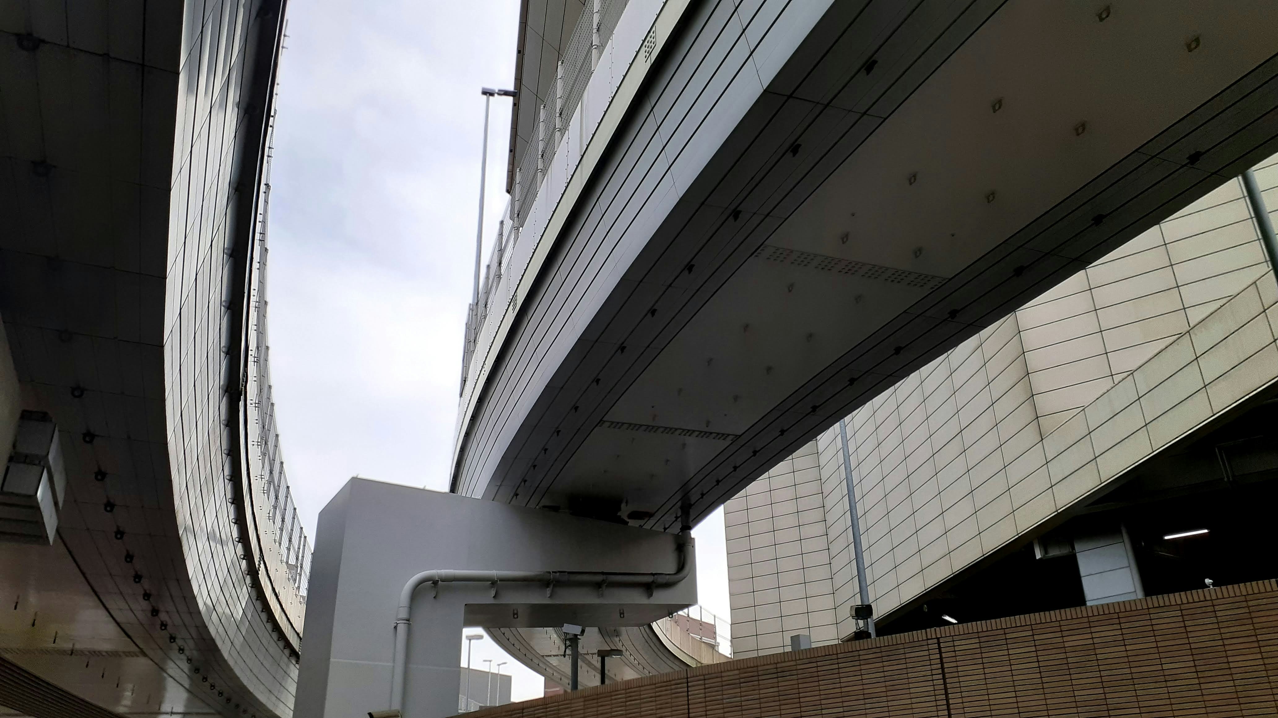 Curved overpass structures intersect against a cloudy sky, showcasing modern architecture.