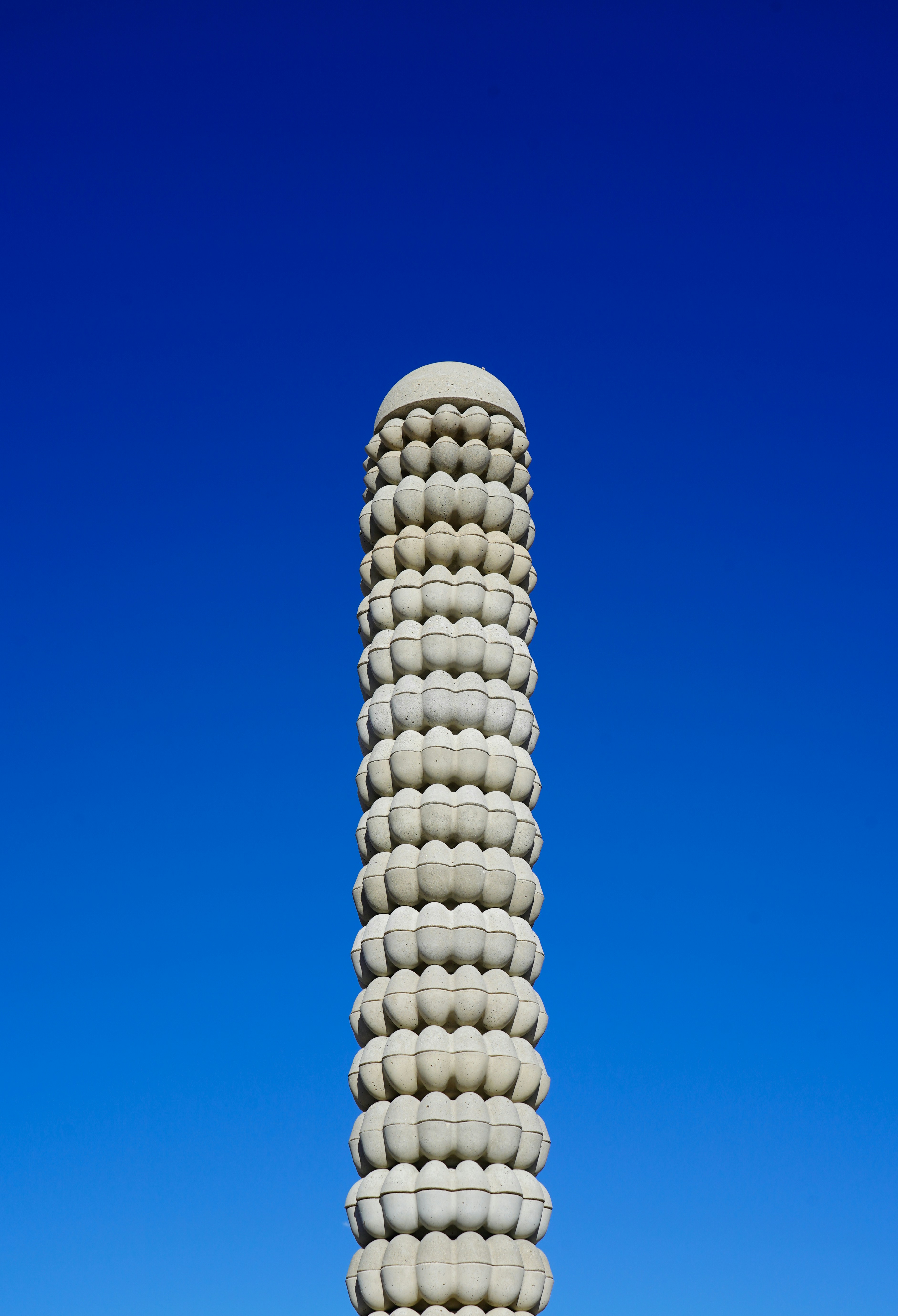 Vertical Beacon: a column of stacked domes against a cobalt sky