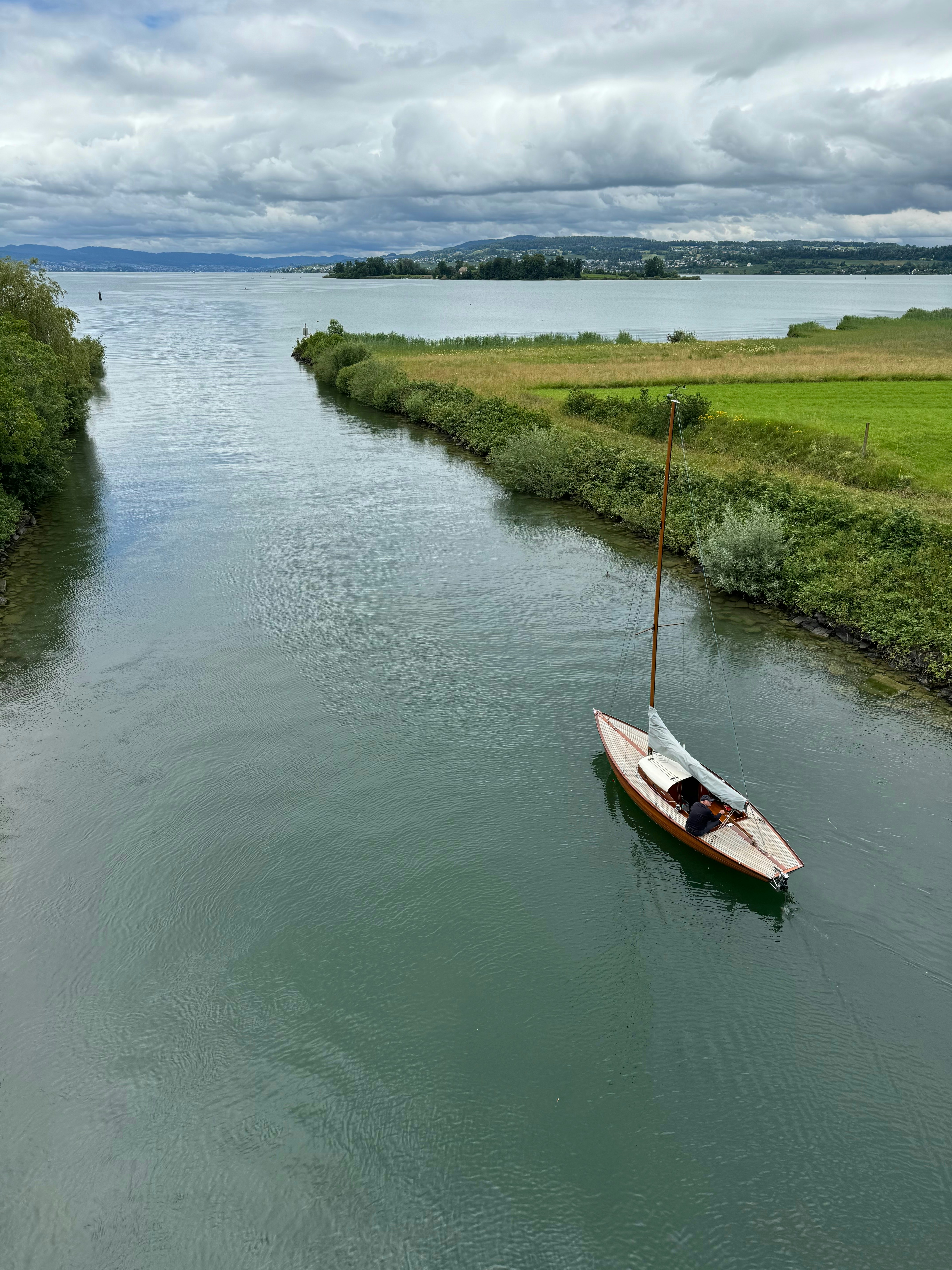 Lone Sailboat in a Meandering River Pocket Under Tempestuous Clouds