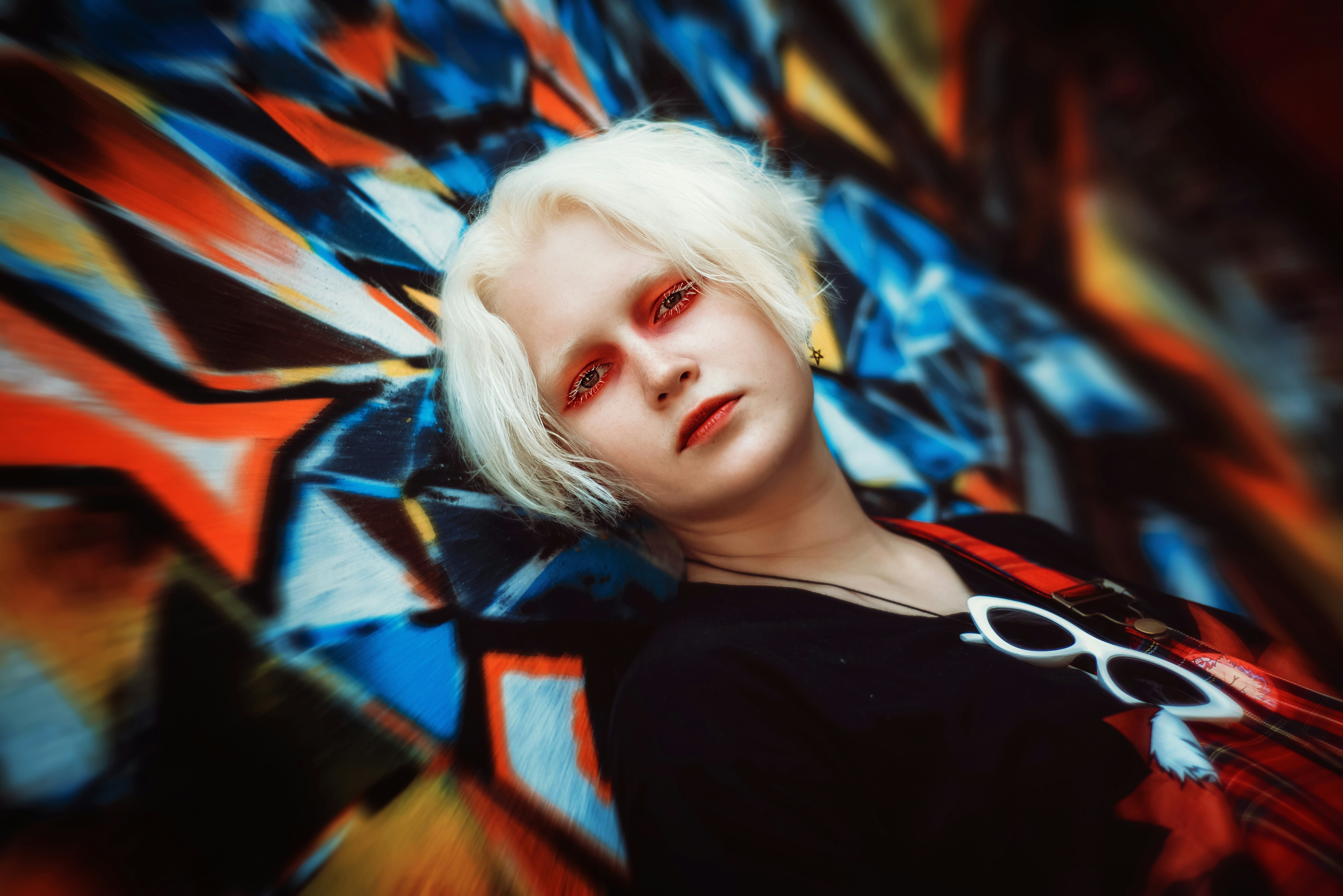 Red-Eyed Moment: Pale Portrait Amidst Kaleidoscopic Graffiti