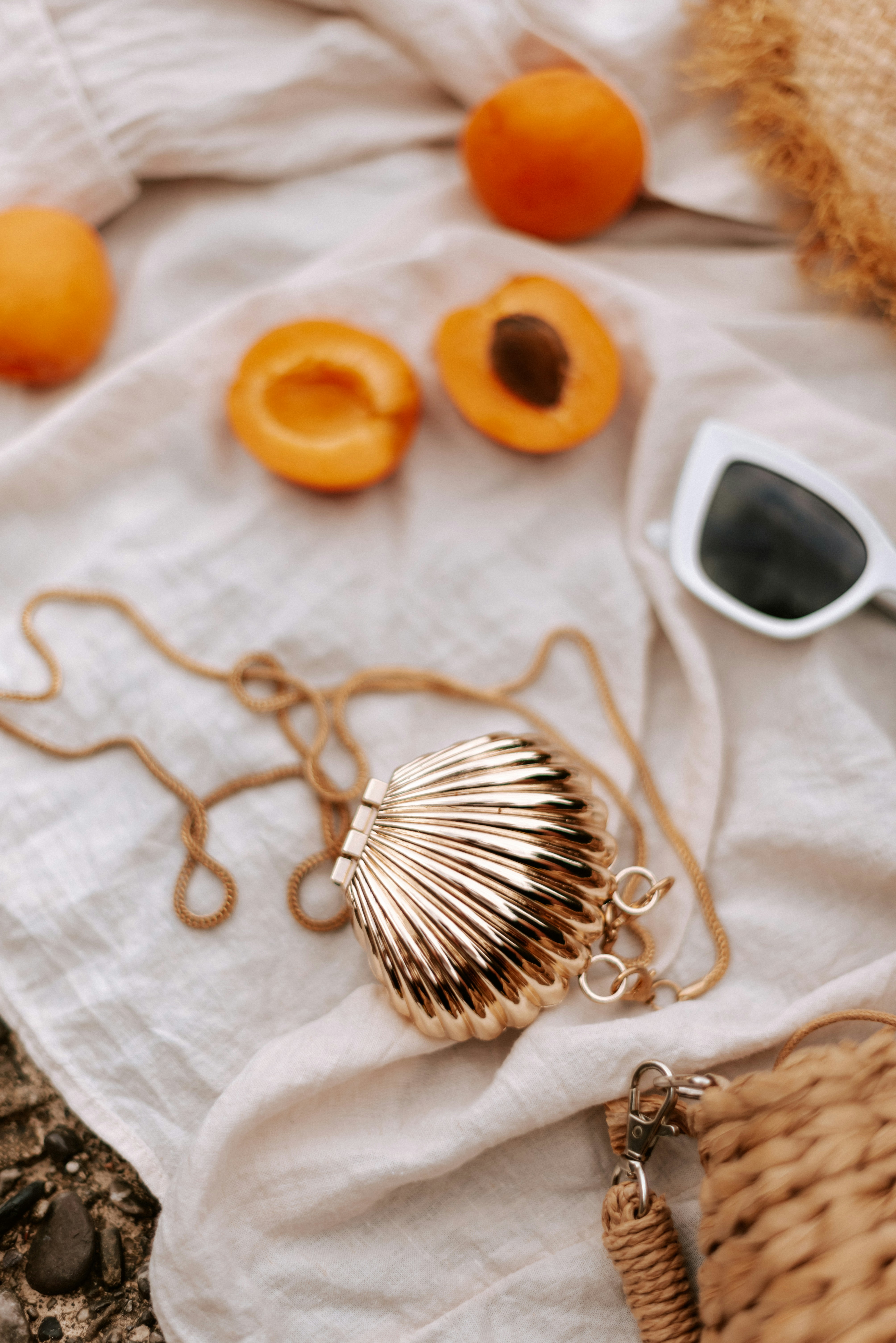 Shimmering Shell Jewelry Resting on Linen with Citrus and Sunglasses