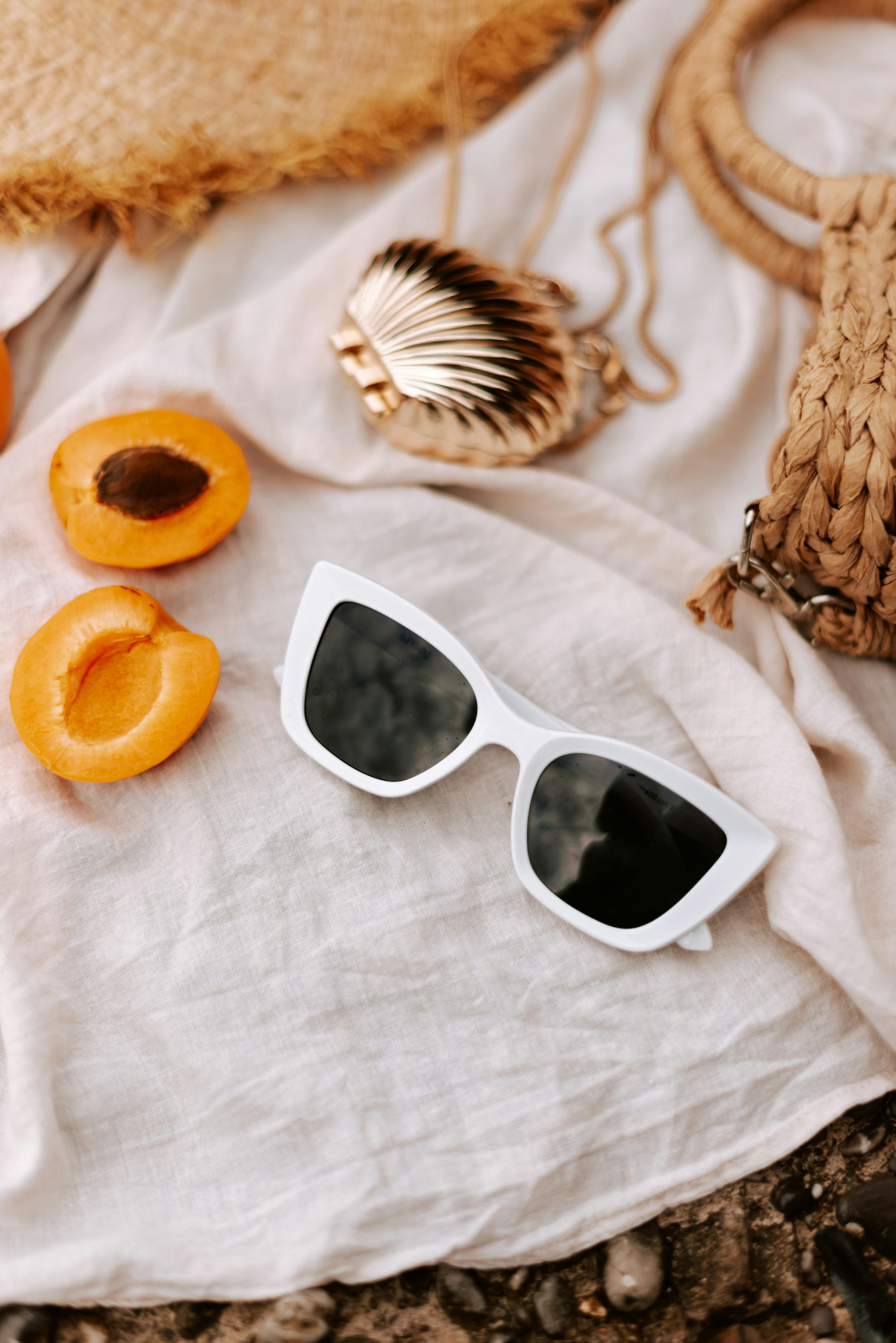 Sunlit Minimalism: White Sunglasses Rest on Linen Amid Apricots and Rope