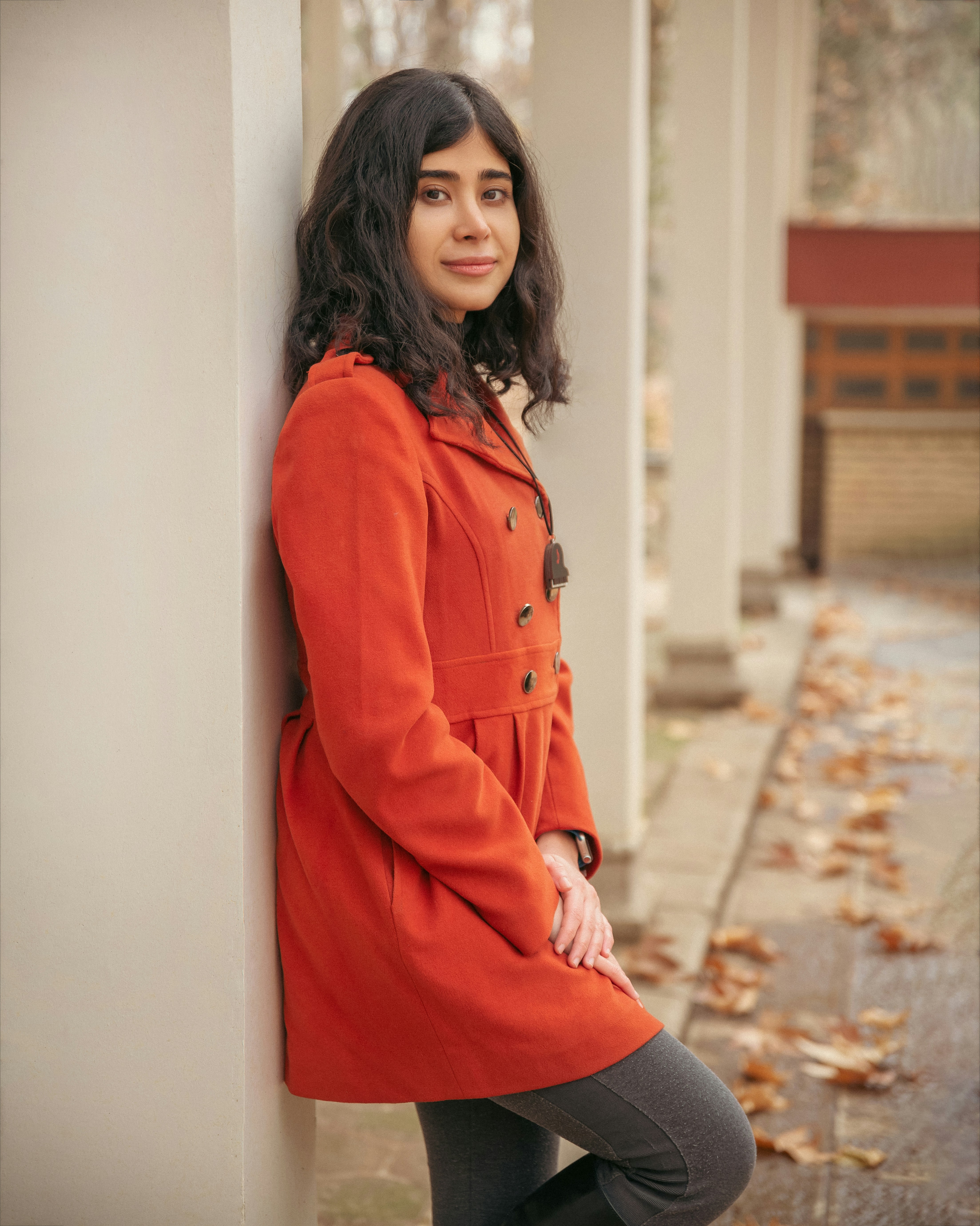 Crimson Coat Portrait Along a Pillar in Autumn Light