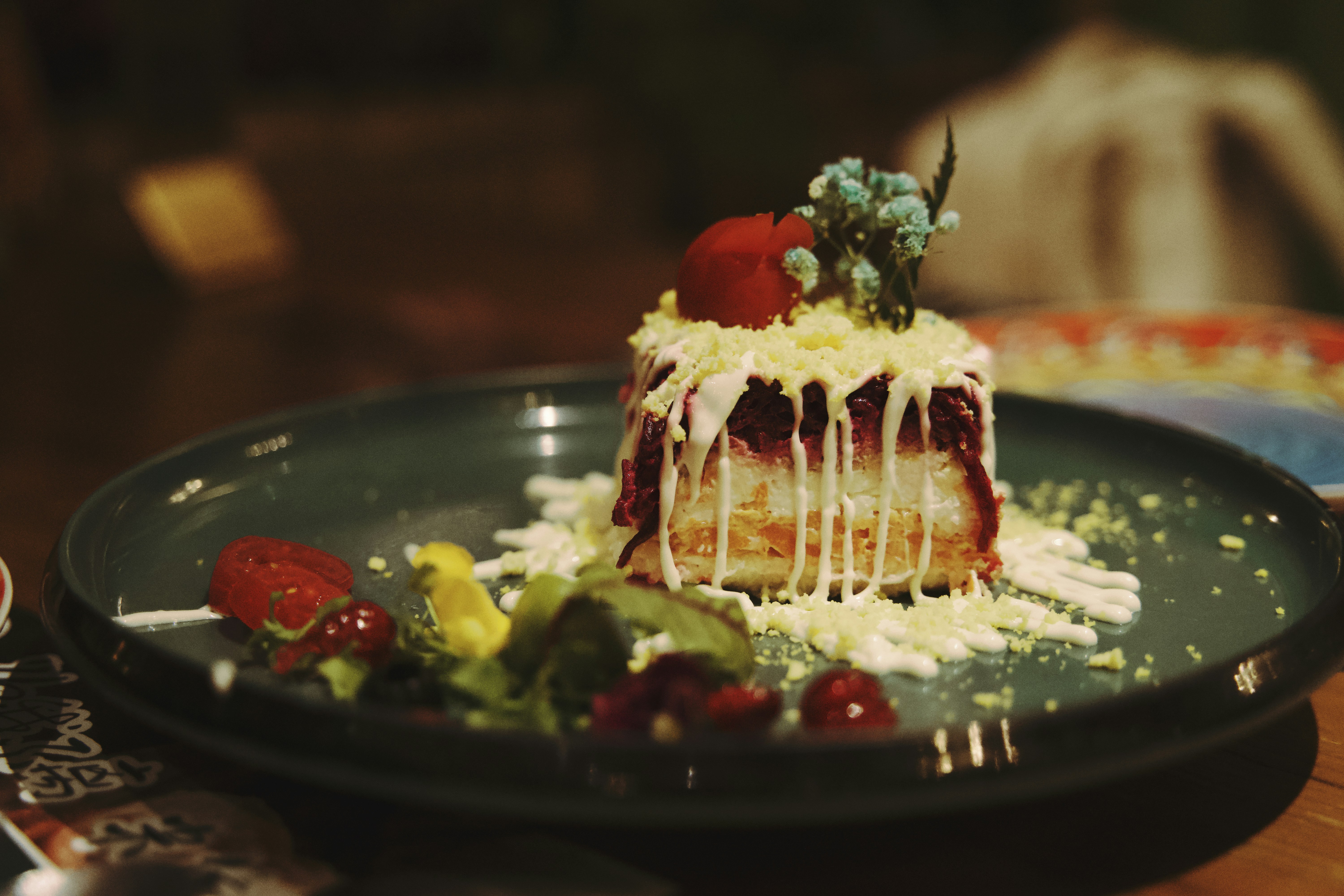 Layered salad with vibrant garnishes, elegantly presented on a dark plate.