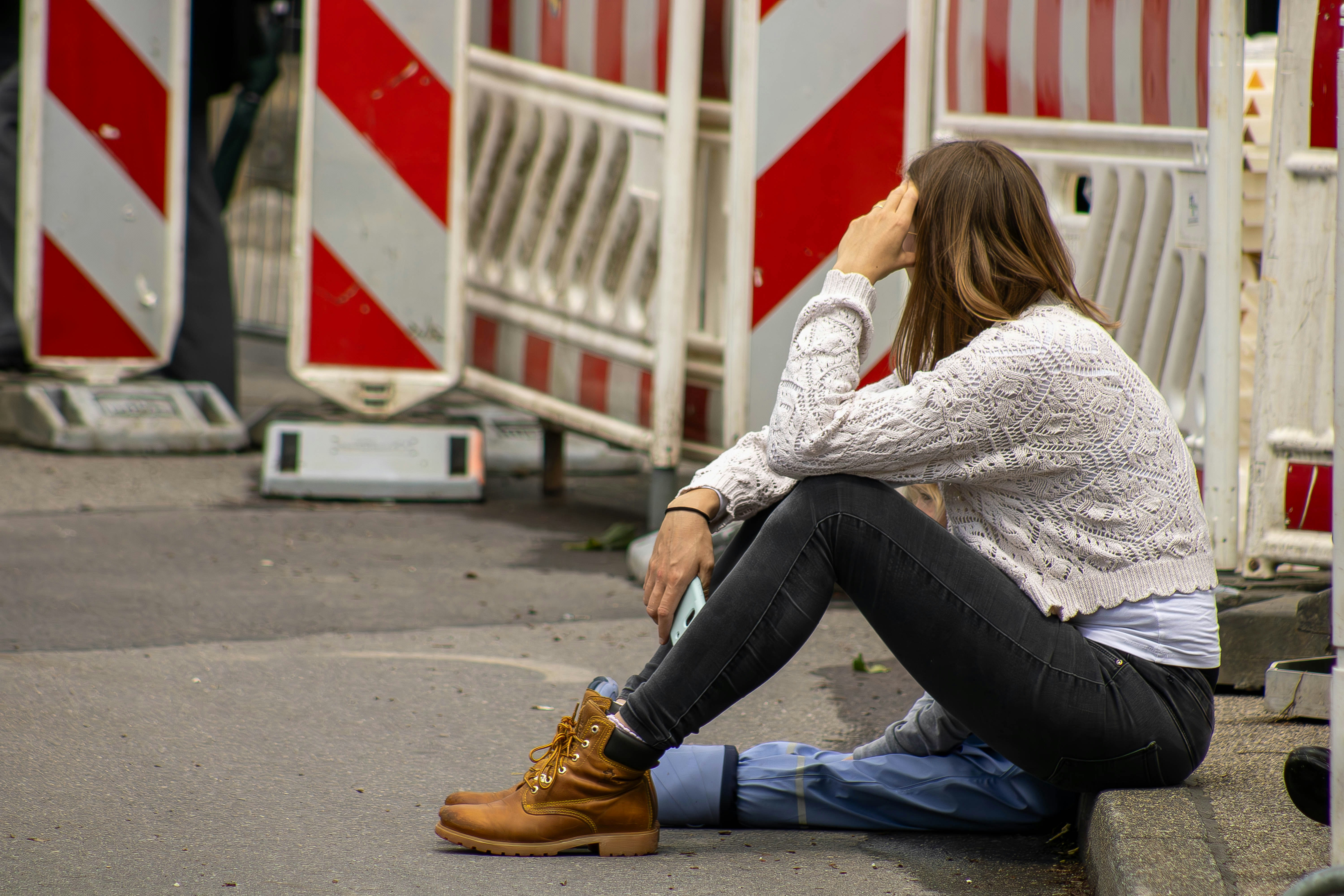 Solitude Near the Barricades: A Woman Pauses on a City Block