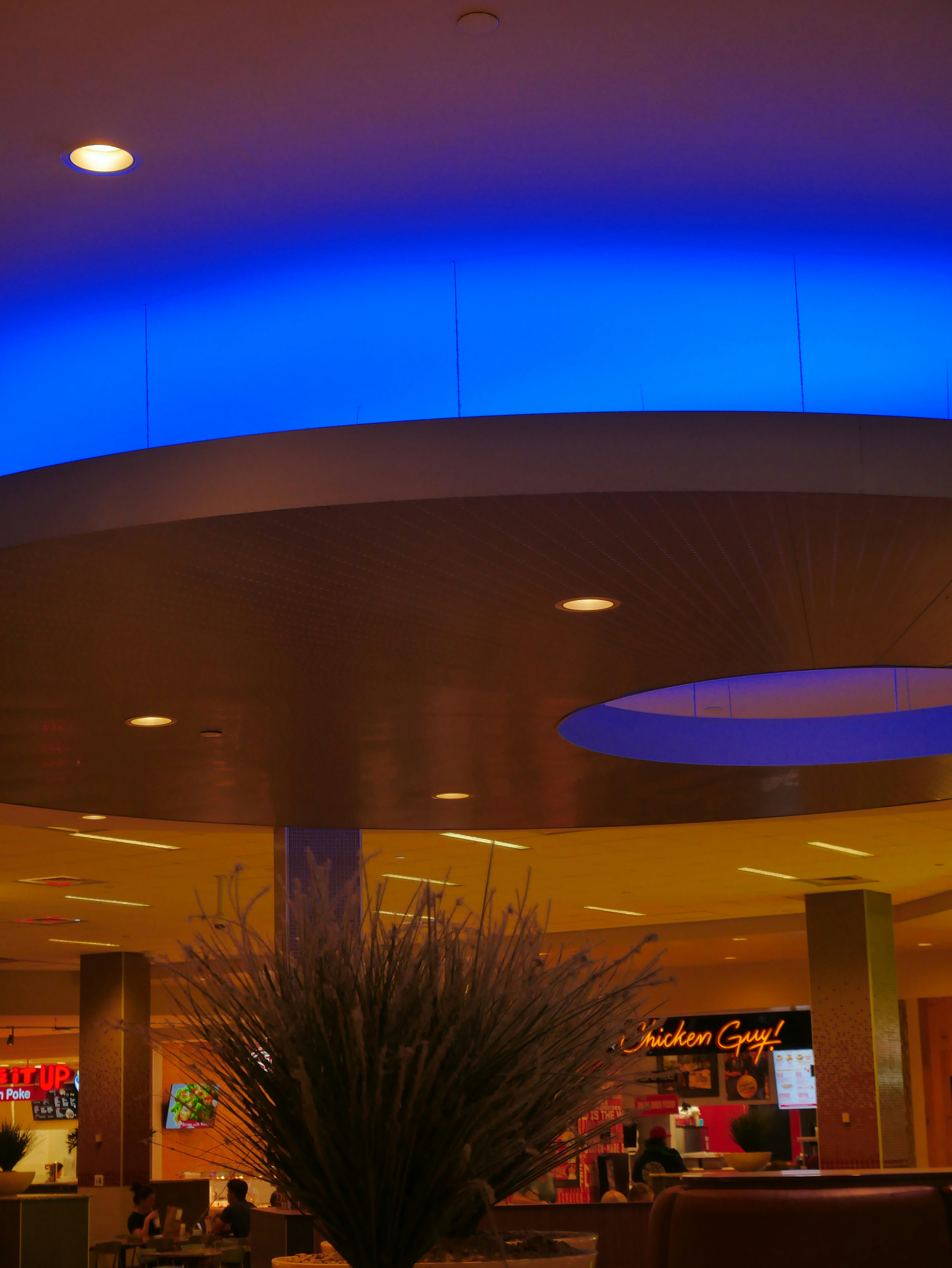 Cobalt Halo Over a Circular Food-Court Atrium