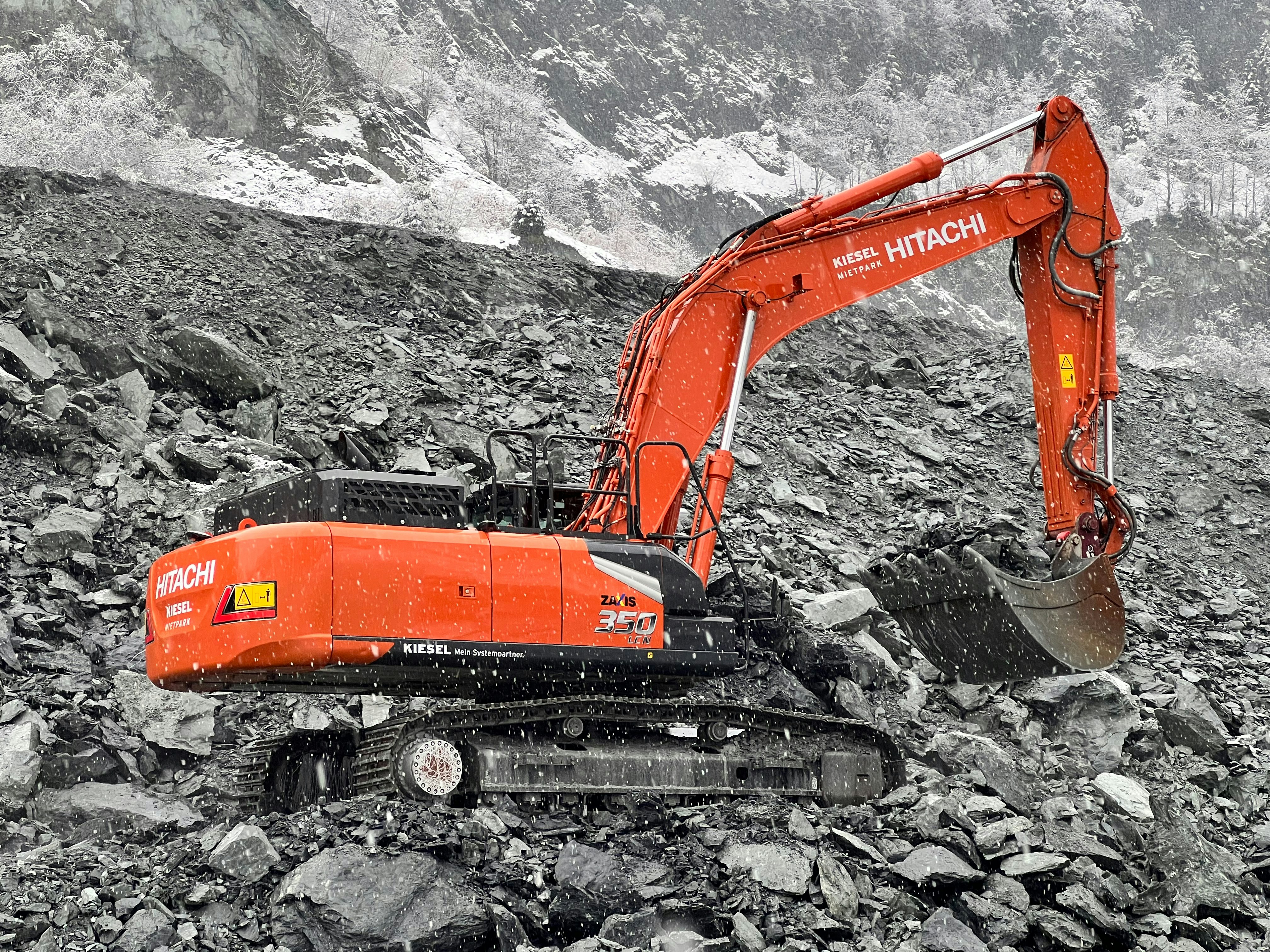 An orange excavator digging through a pile of rocks photo – Free Bagger ...