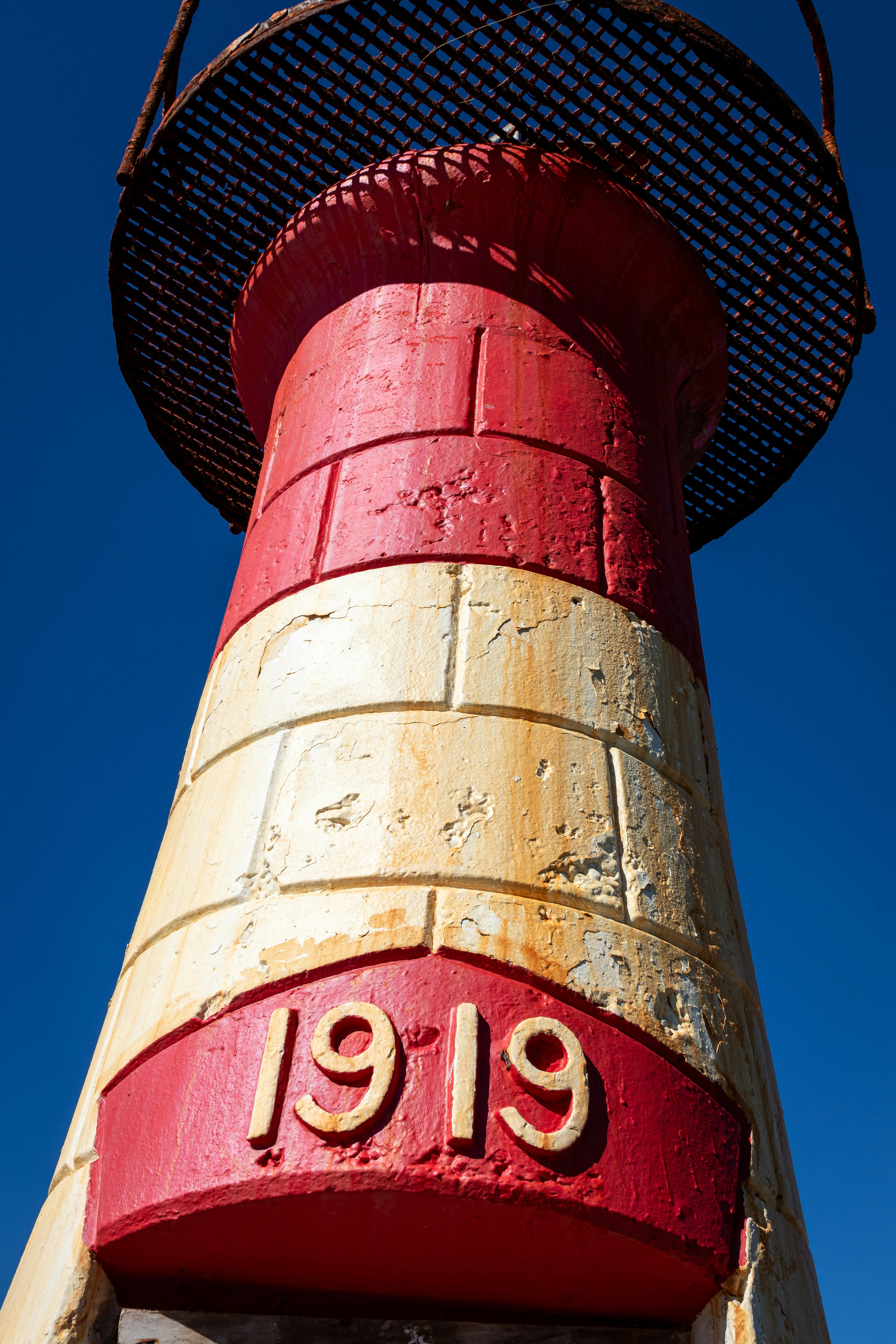 1919 Lighthouse: A Time-Worn Red-Topped Pillar Against a Cerulean Sky