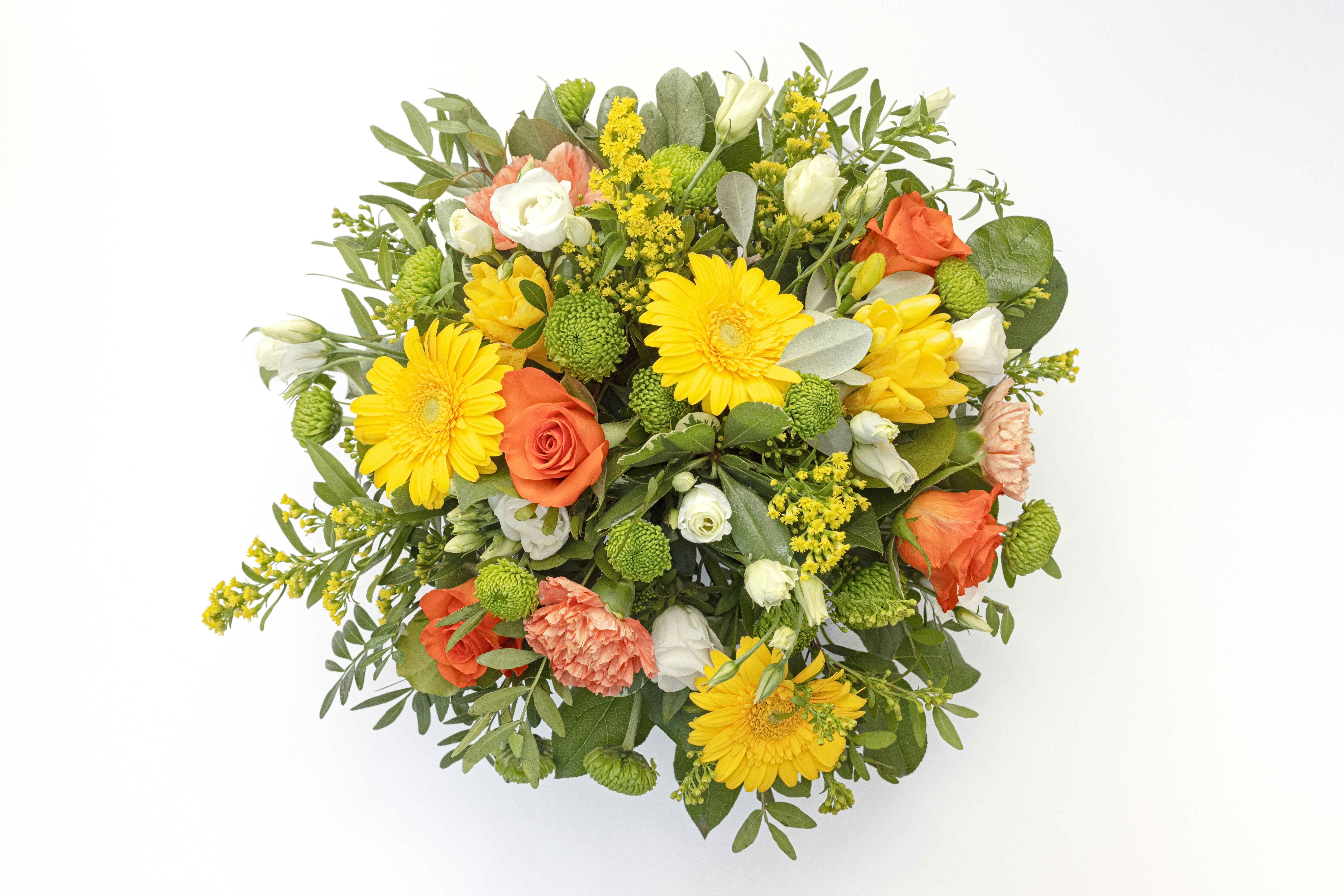Top view of an arrangement of yellow, orange and white flowers, with green foliage, set against a white background.