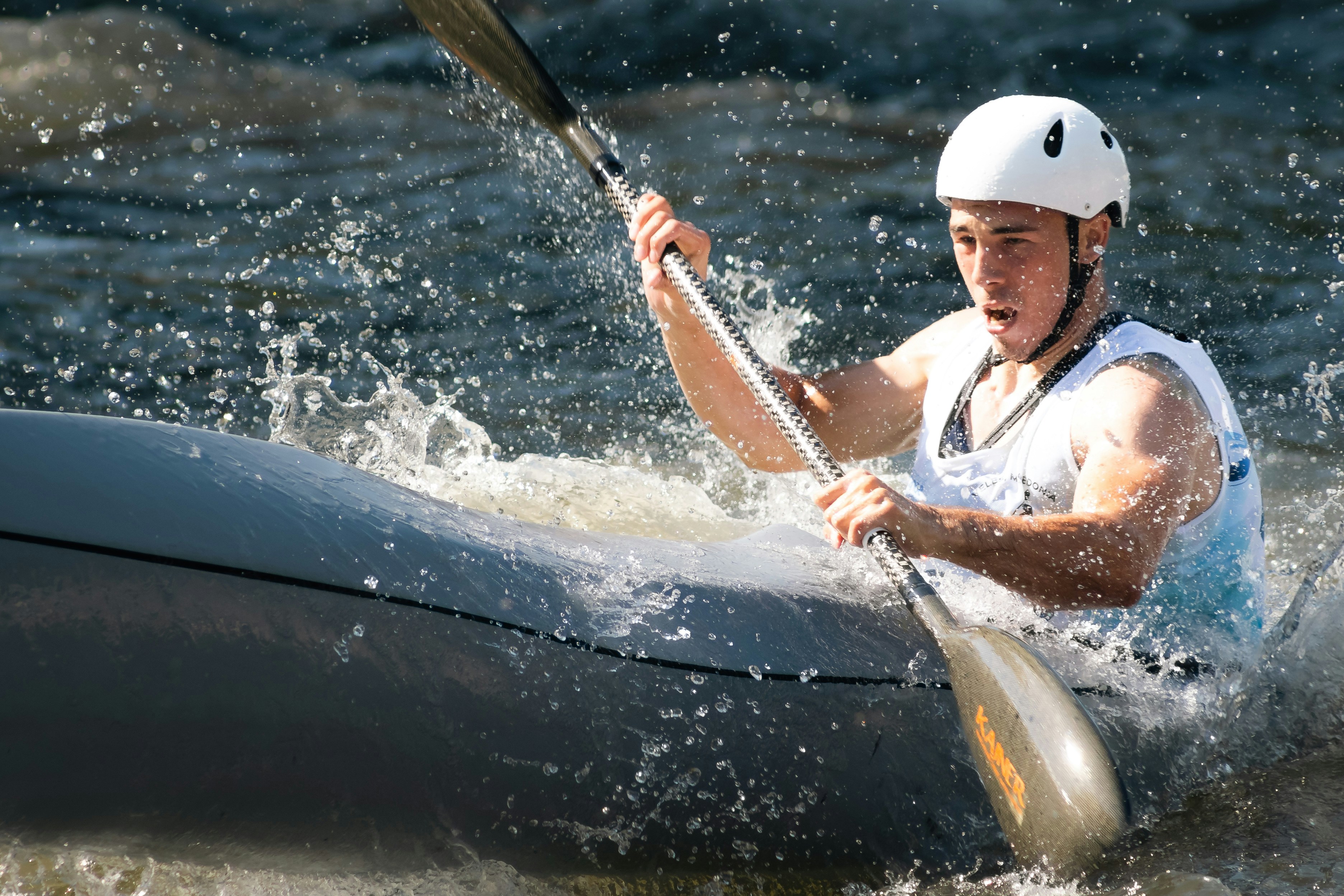 White-Helmet Kayaker Surges Through Sunlit Whitewater