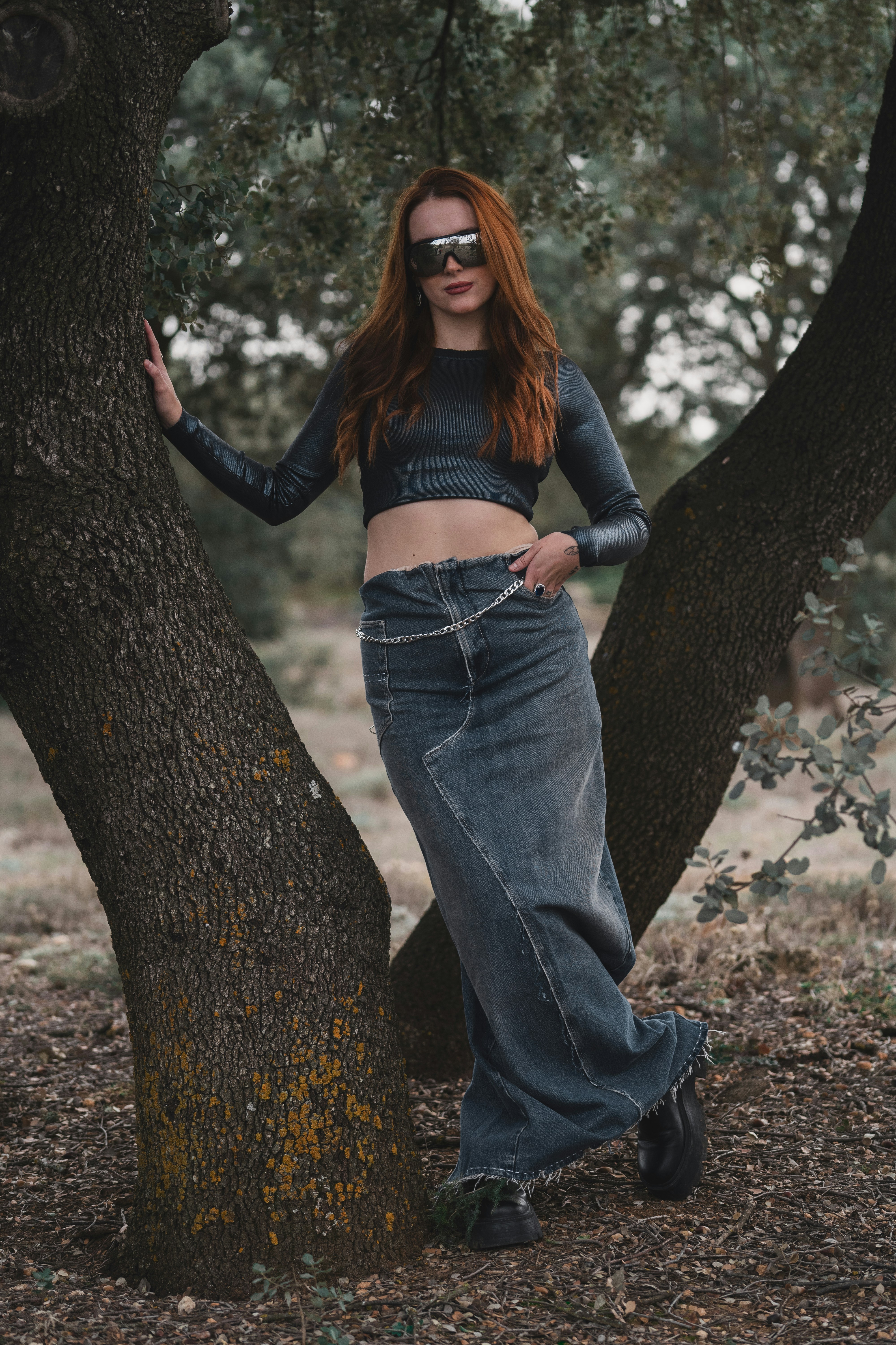 Red-Haired Muse Between Tree Trunks in Dappled Forest Light
