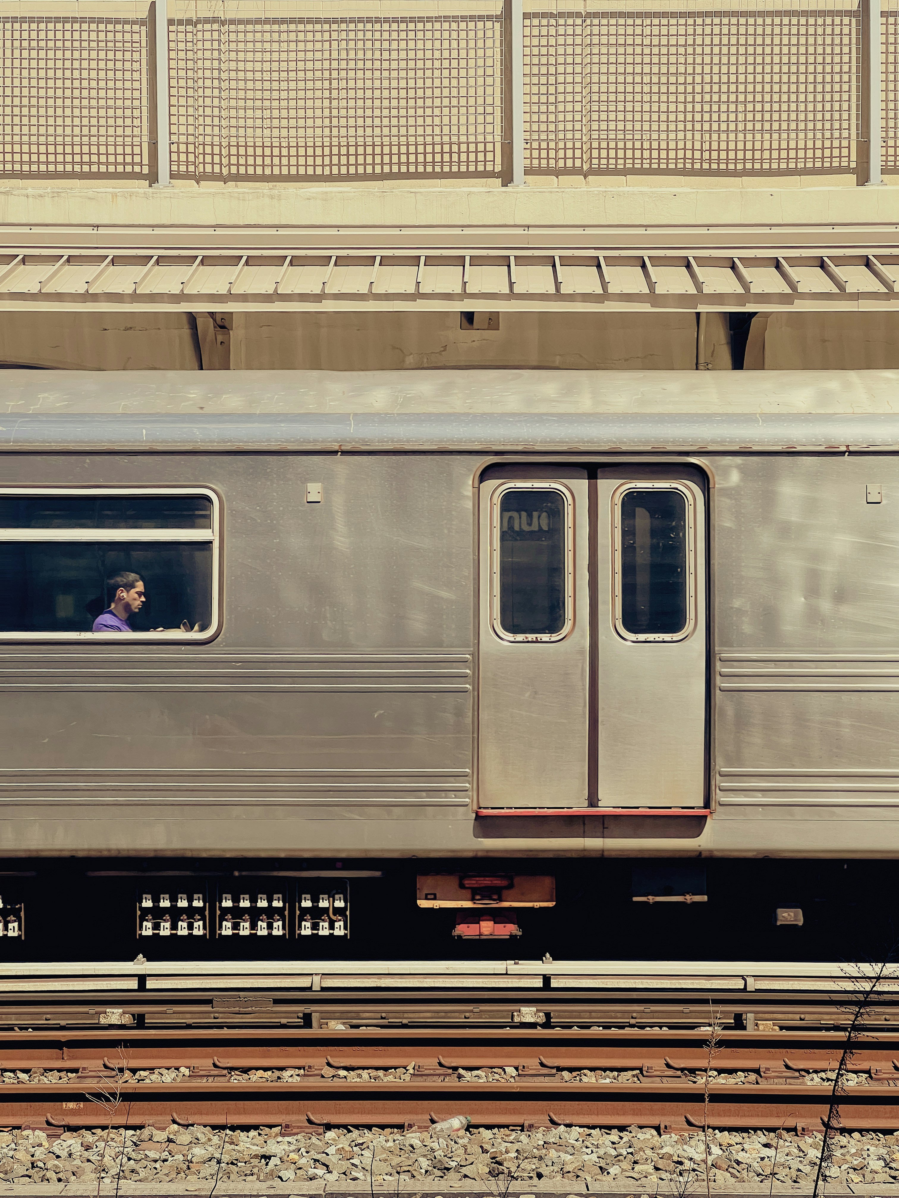 A silver train traveling down train tracks next to a building