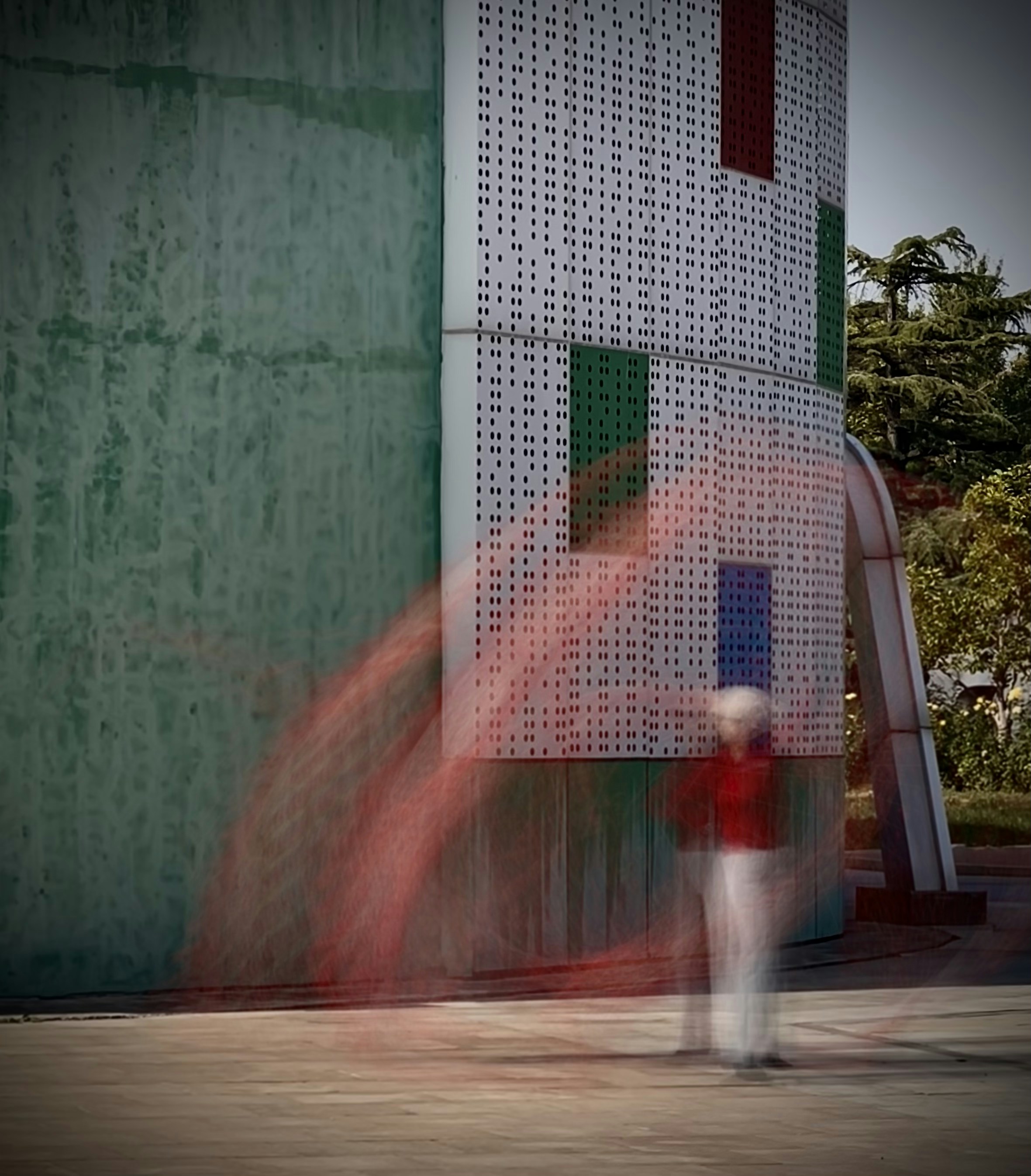 Red Motion Arc Tracing a Geometric Wall in a Quiet Courtyard