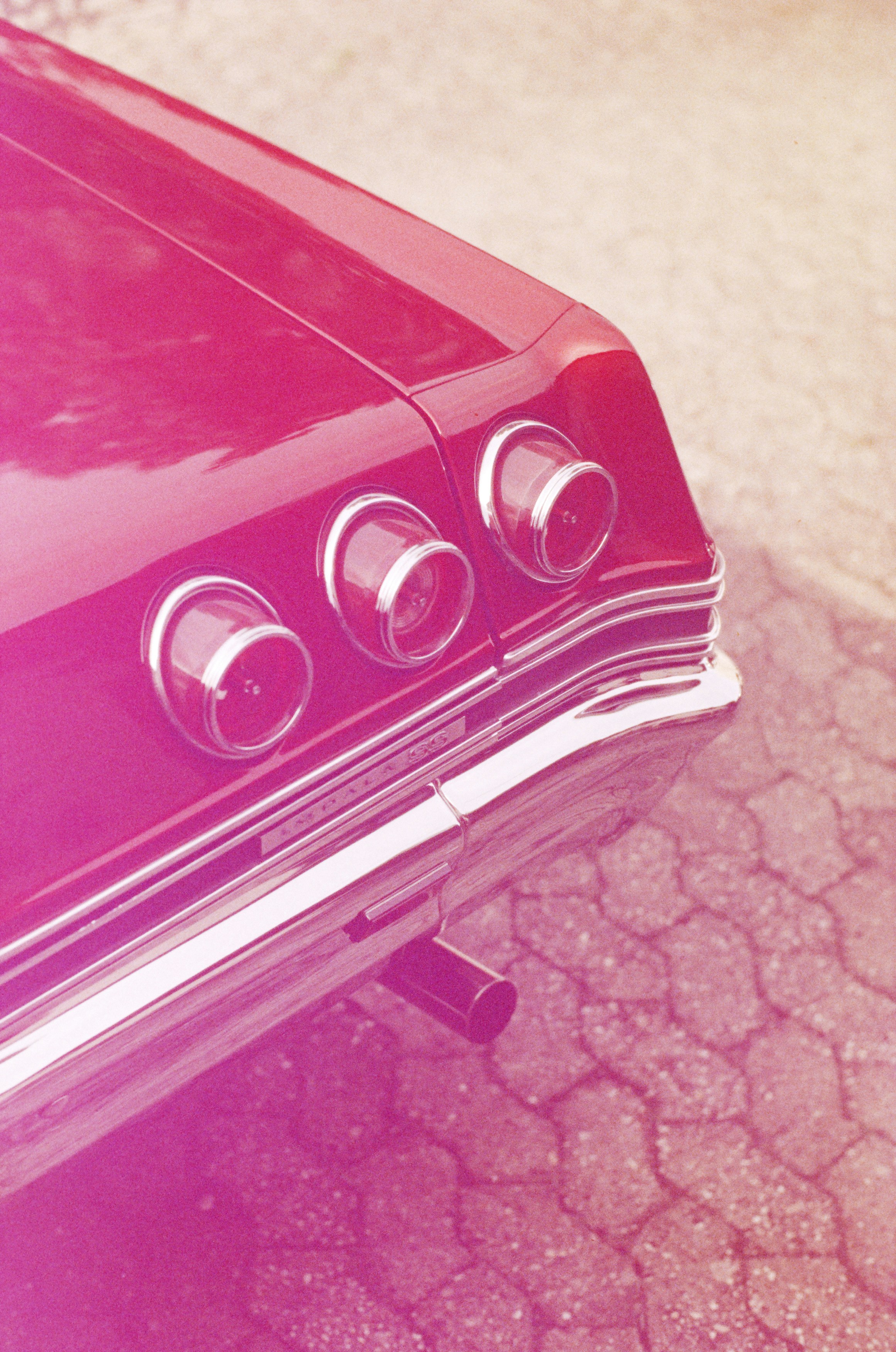 Close-up of a classic car's rear lights and chrome details, highlighted by vibrant hues.
