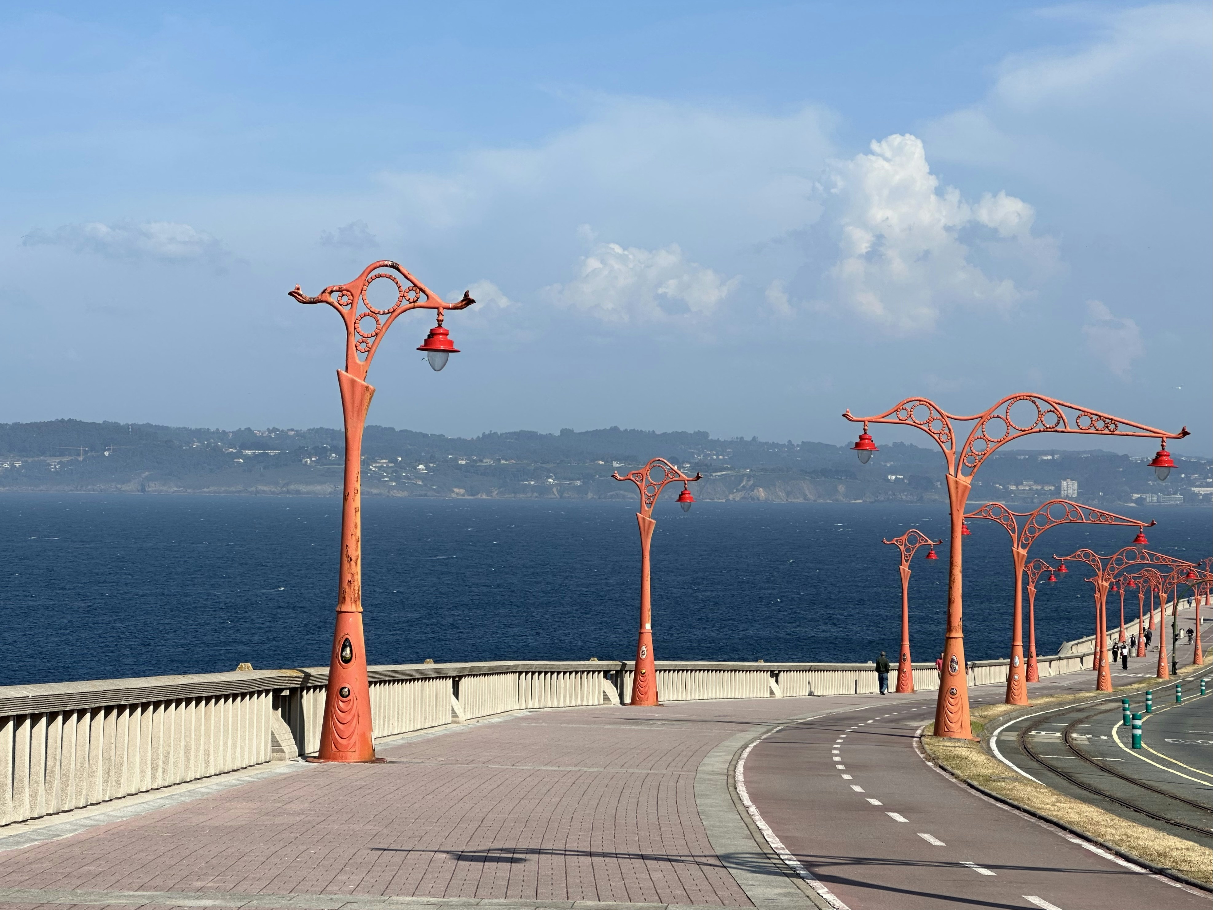 Orange Lanterns Trace a Curved Seaside Promenade Under a Wide Blue Sky