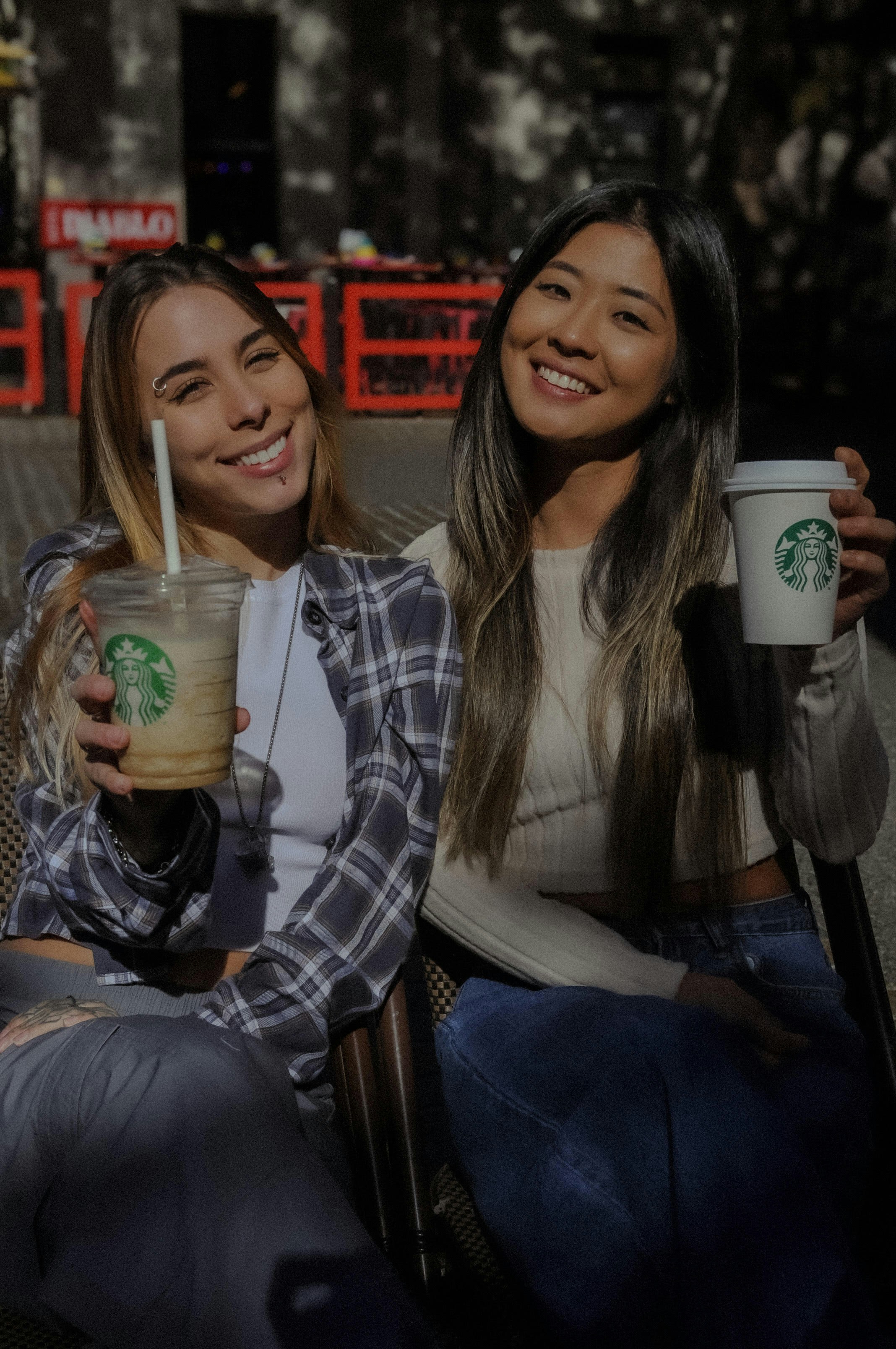Two women sitting on a bench holding starbucks drinks photo – Free ...