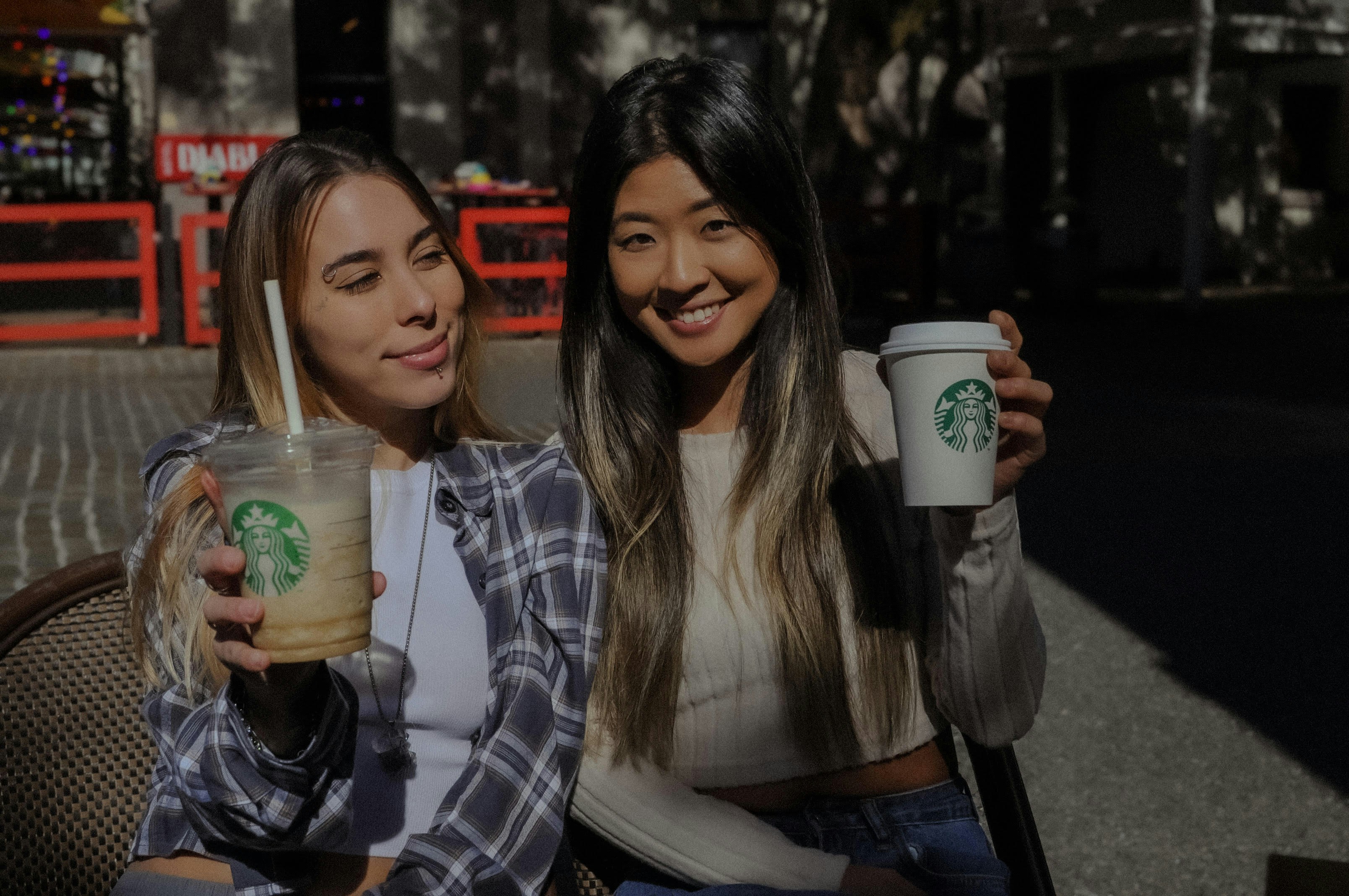 Two women sitting on a bench holding starbucks drinks photo – Free Face ...