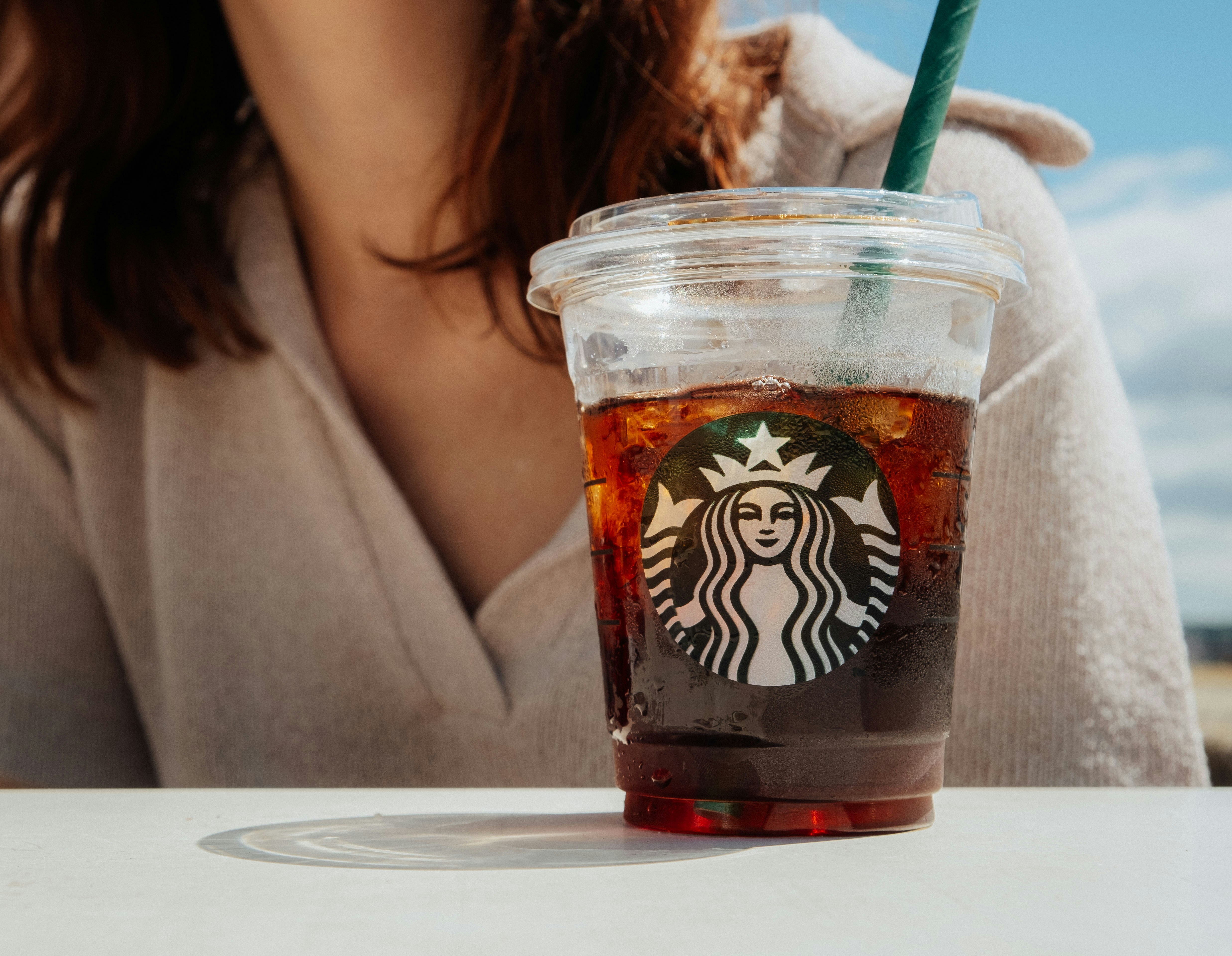 Starbucks Cup in Focus: A Close-Up of a Cold Drink with a Clouded Skyline