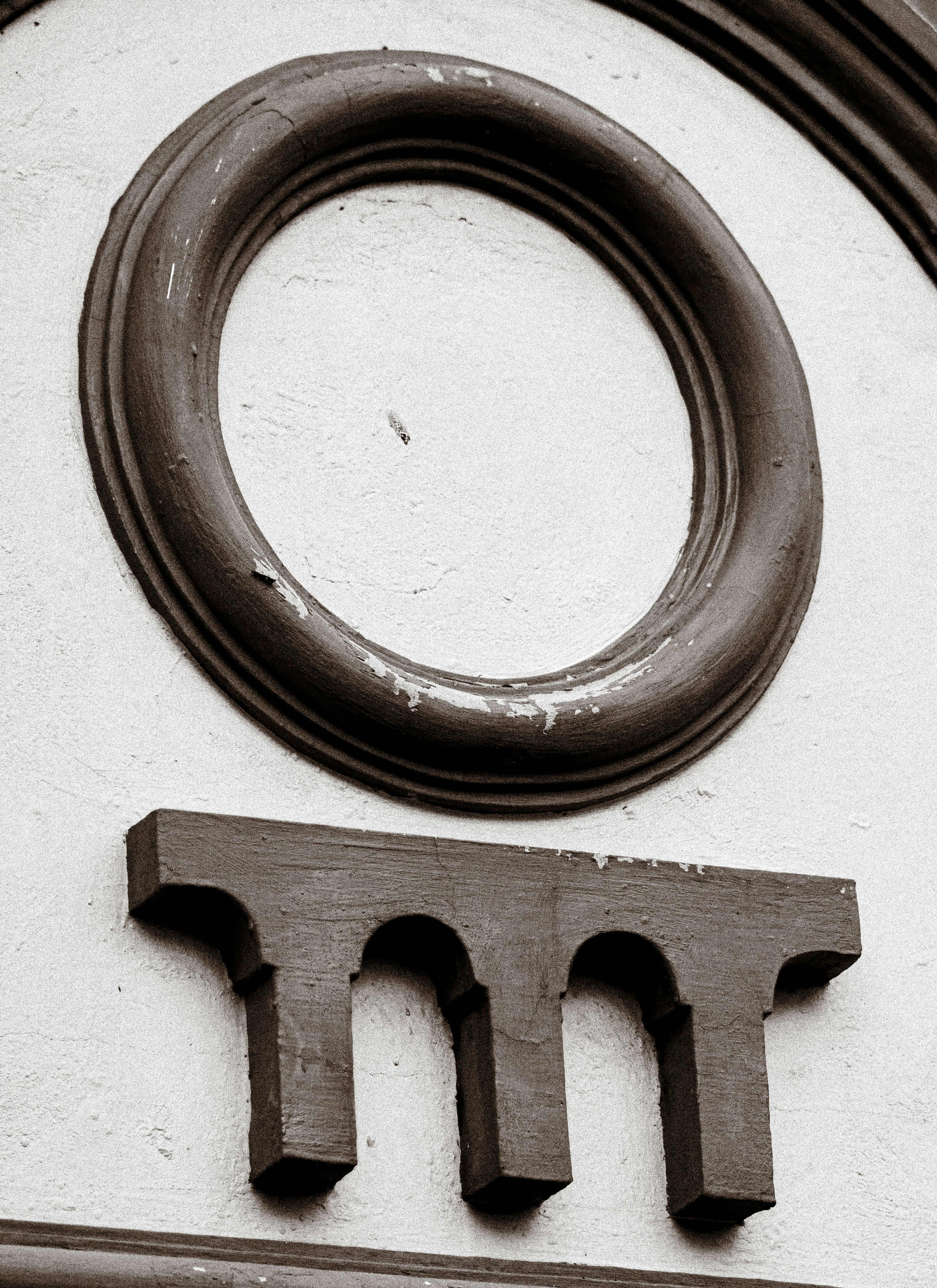 Sepia Close-Up: Ring Above Arched Carvings on Weathered Facade