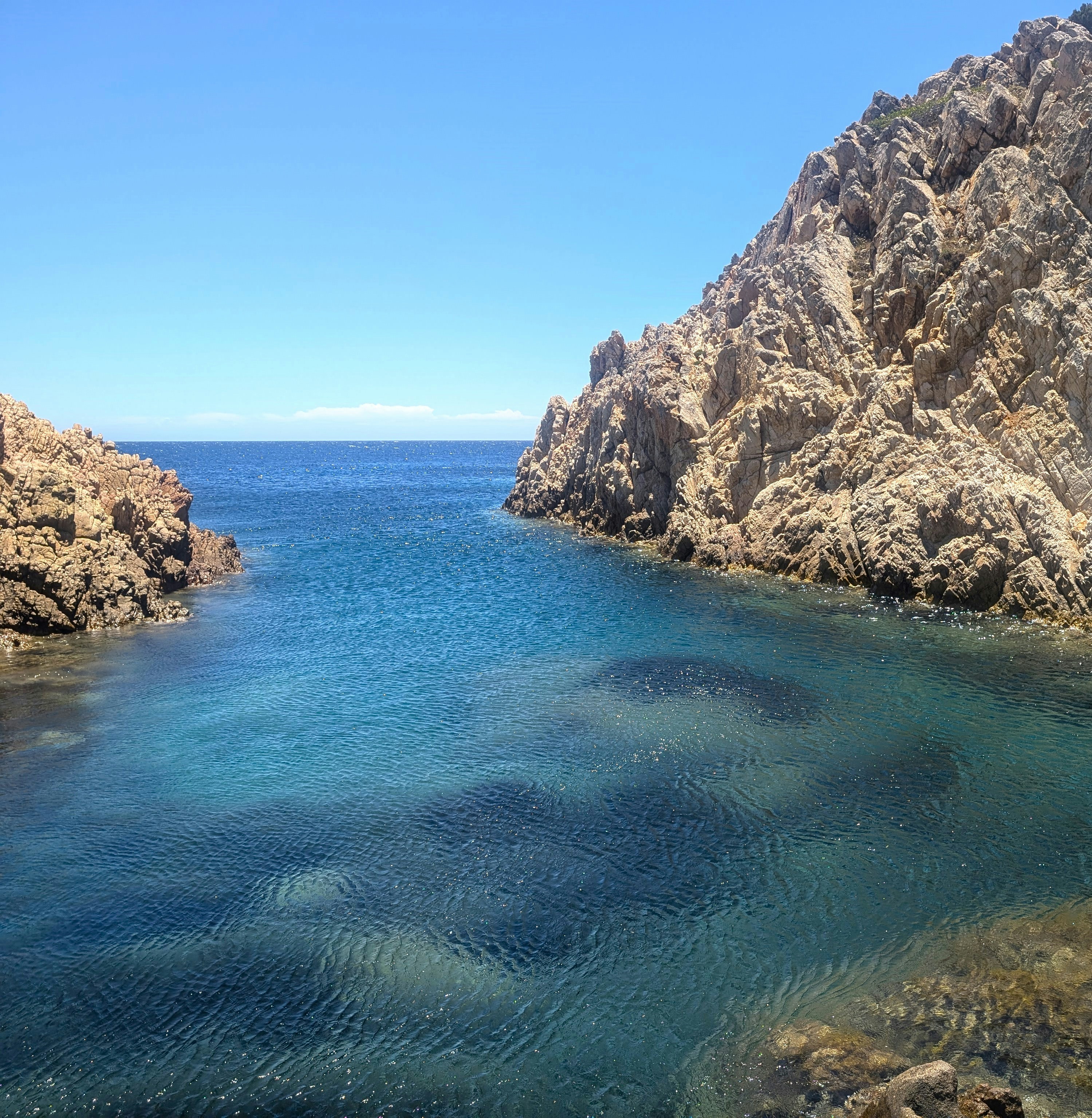 A large body of water surrounded by rocks photo – Free Sea Image on ...