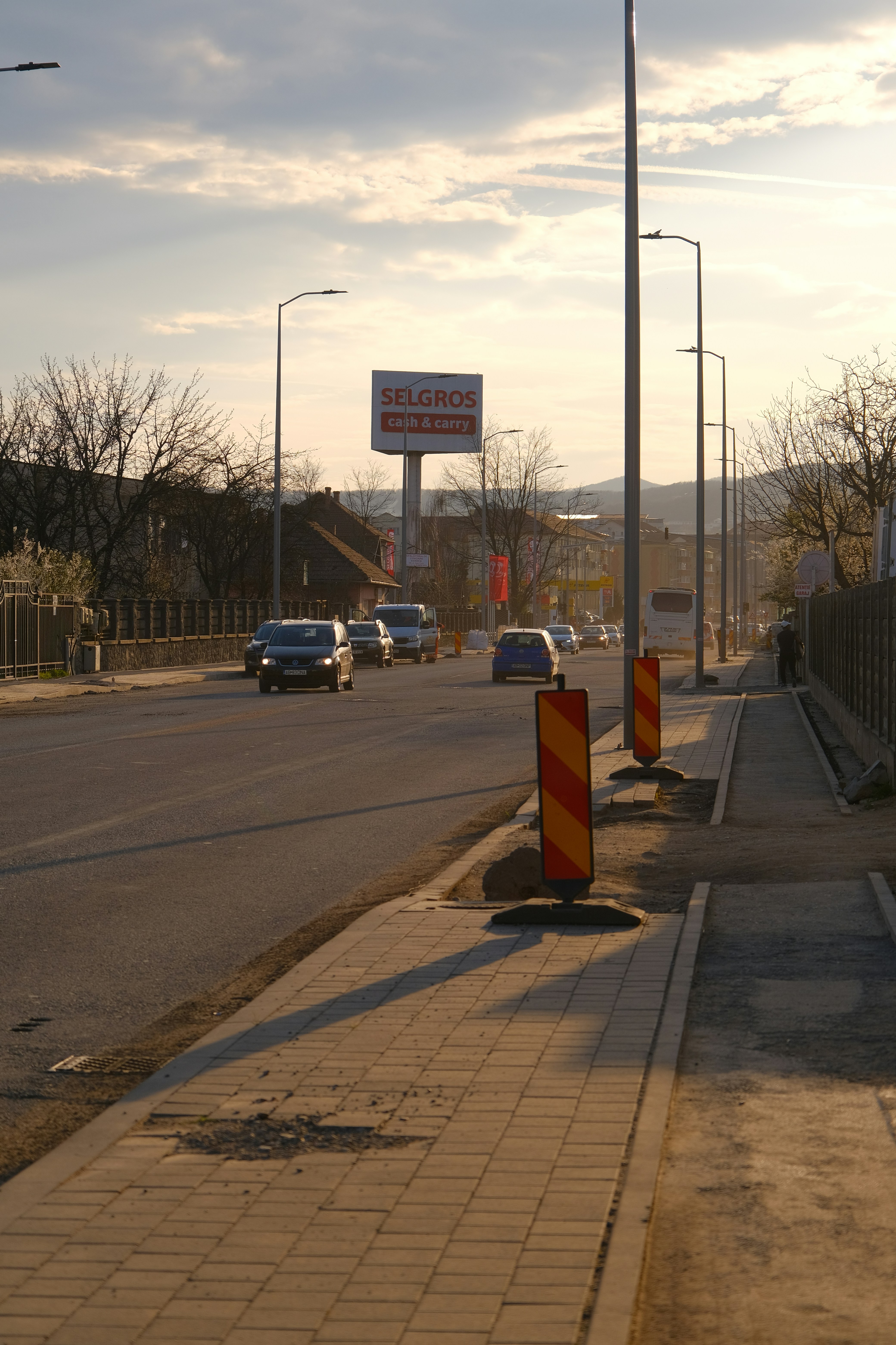 Selgros at Dusk: A Quiet Street Framed by Barriers and Streetlights