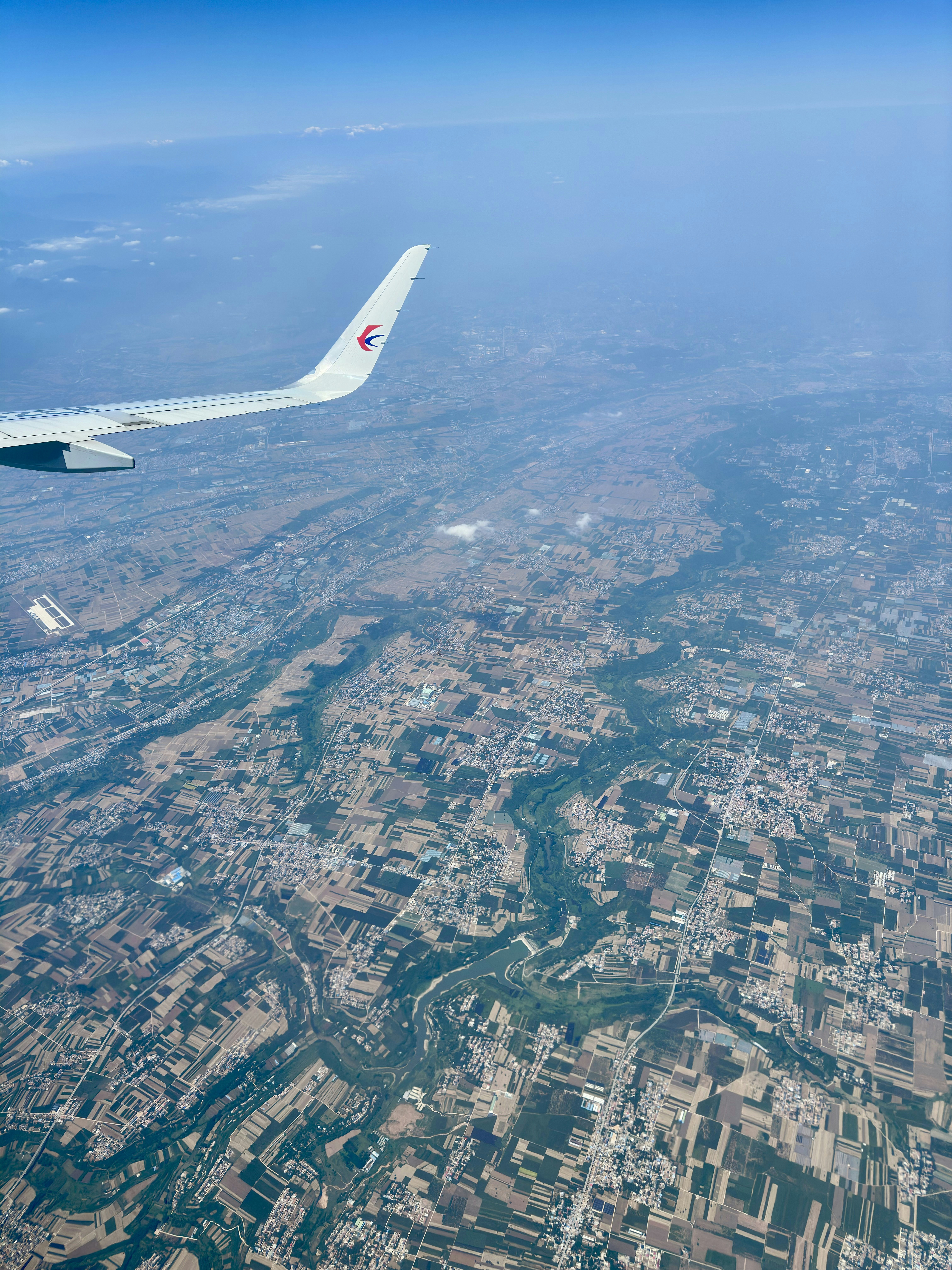 Patchwork from Above: Wing and Farmland Unfold Beneath a Jet