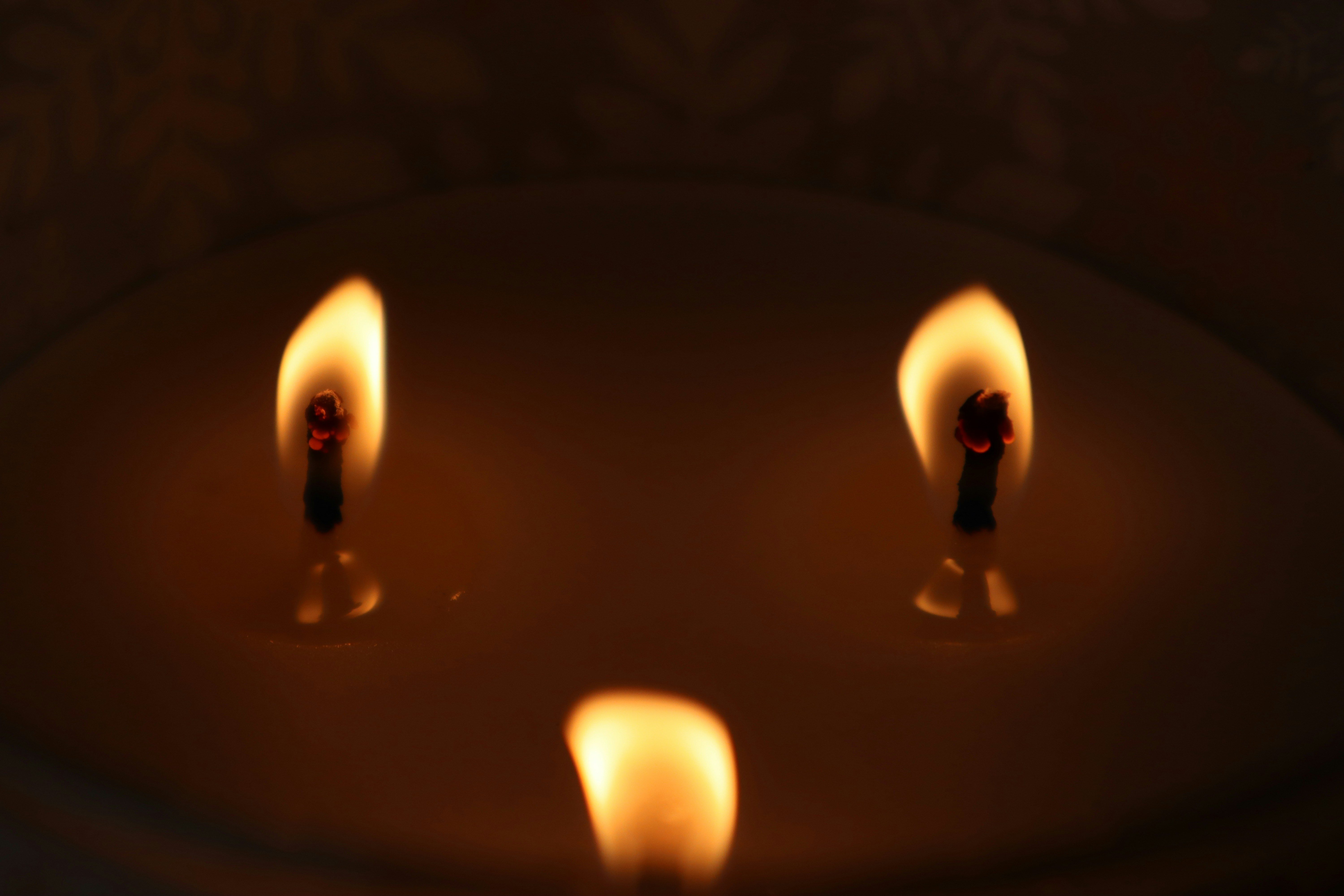 Warm glow of three candle flames casting gentle light in a darkened room.
