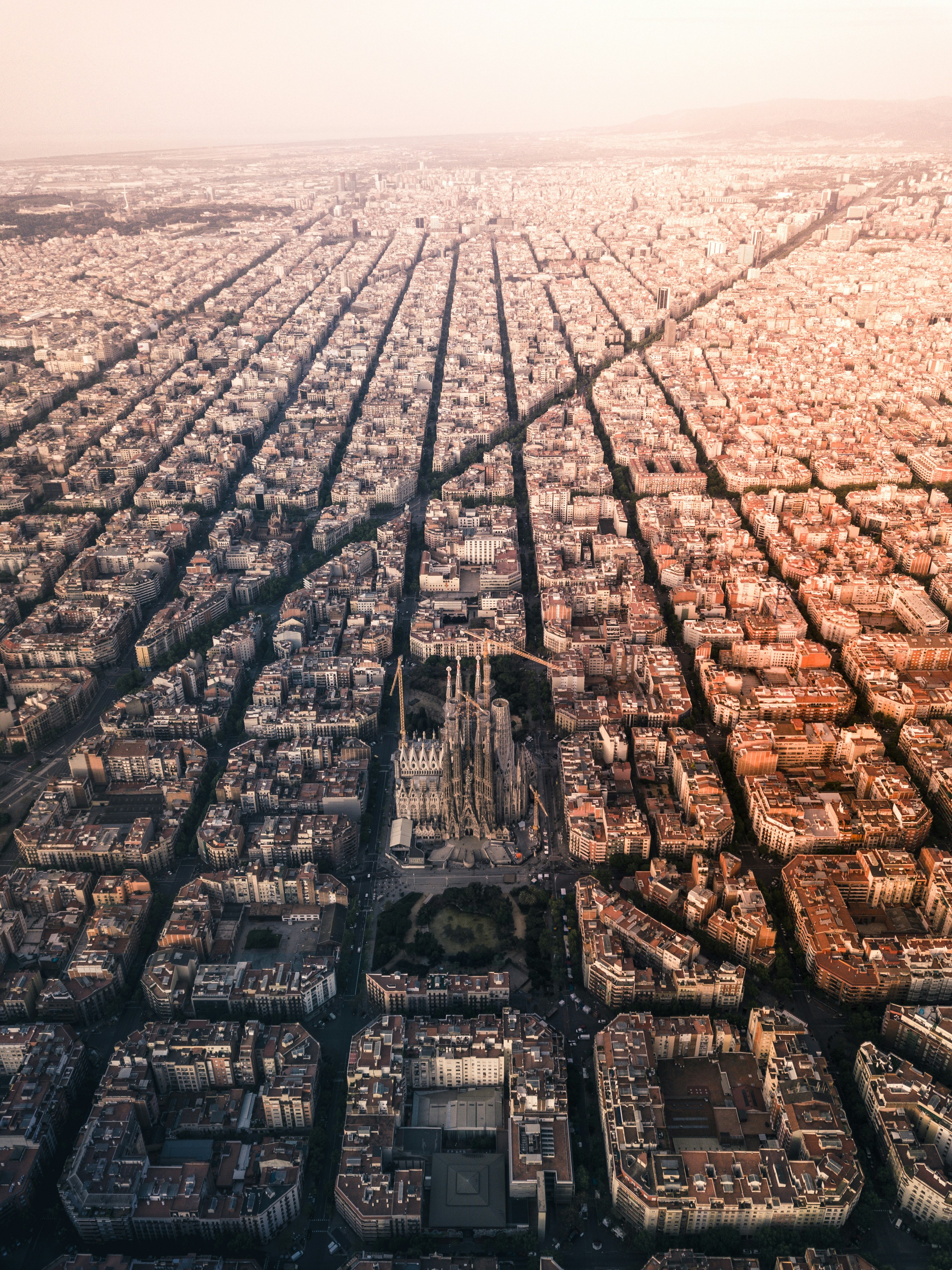 Aerial view of Barcelona showcasing its intricate grid layout, with the iconic Sagrada Família standing prominently amidst the urban landscape.